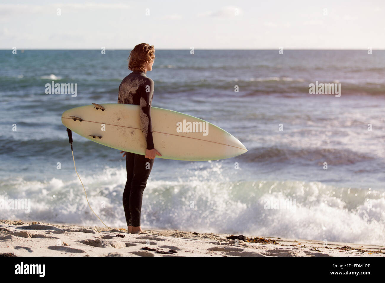 A surfer with his surfboard at the beach Stock Photo - Alamy