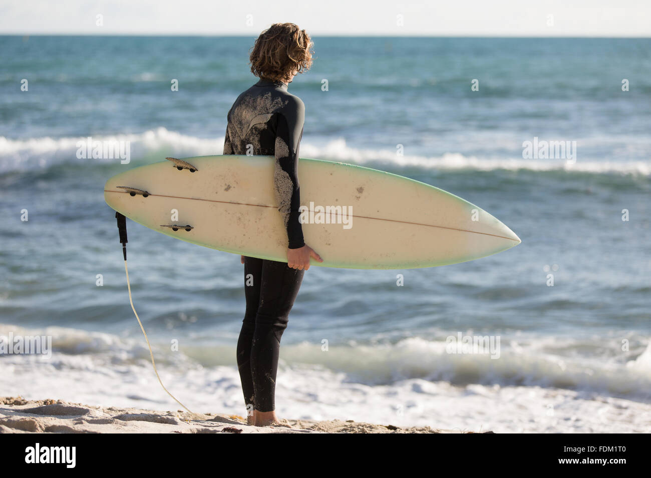 A surfer with his surfboard at the beach Stock Photo - Alamy