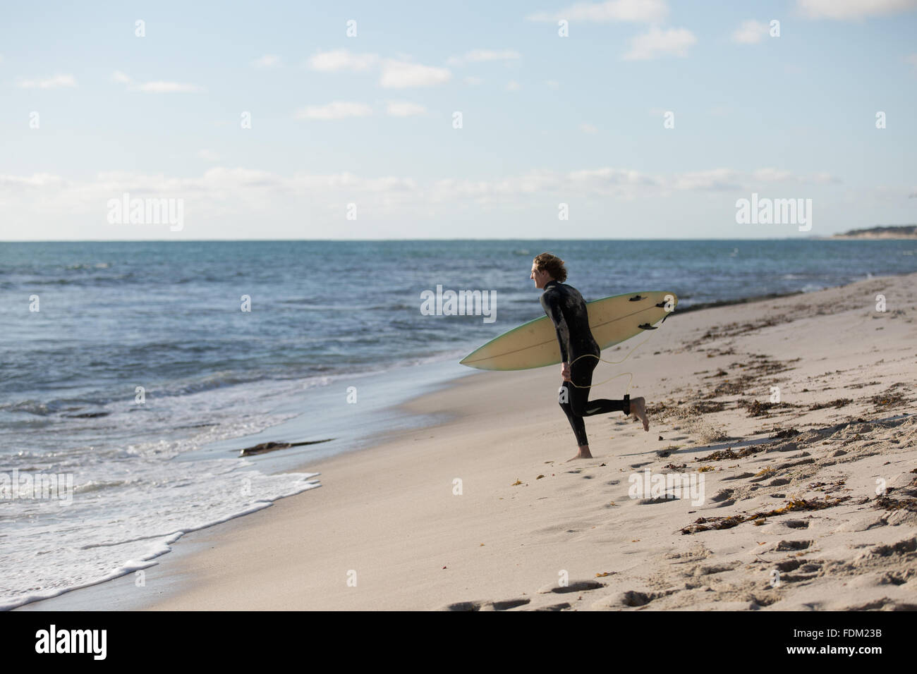 A surfer with his surfboard at the beach Stock Photo - Alamy