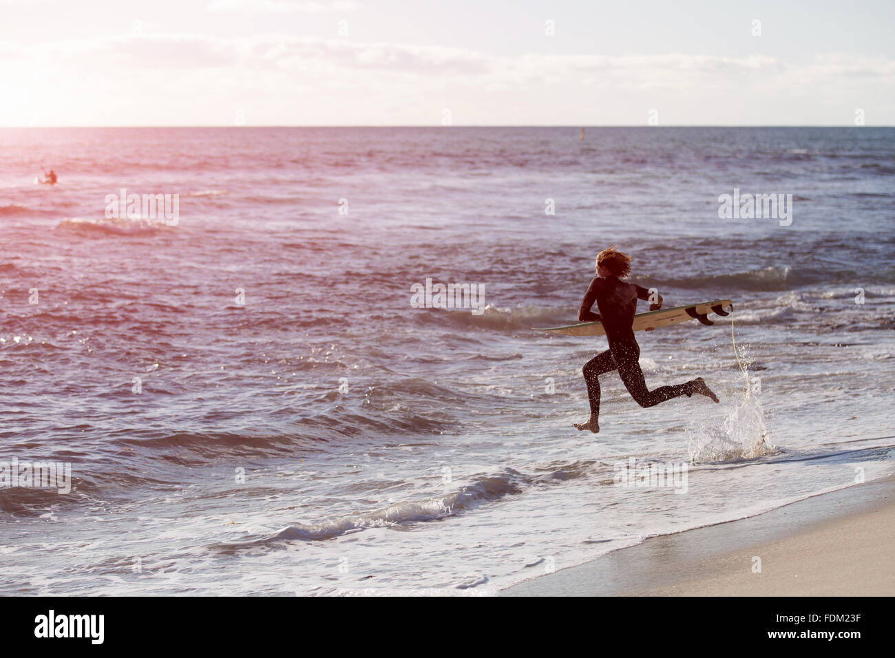 A surfer with his surfboard at the beach Stock Photo - Alamy