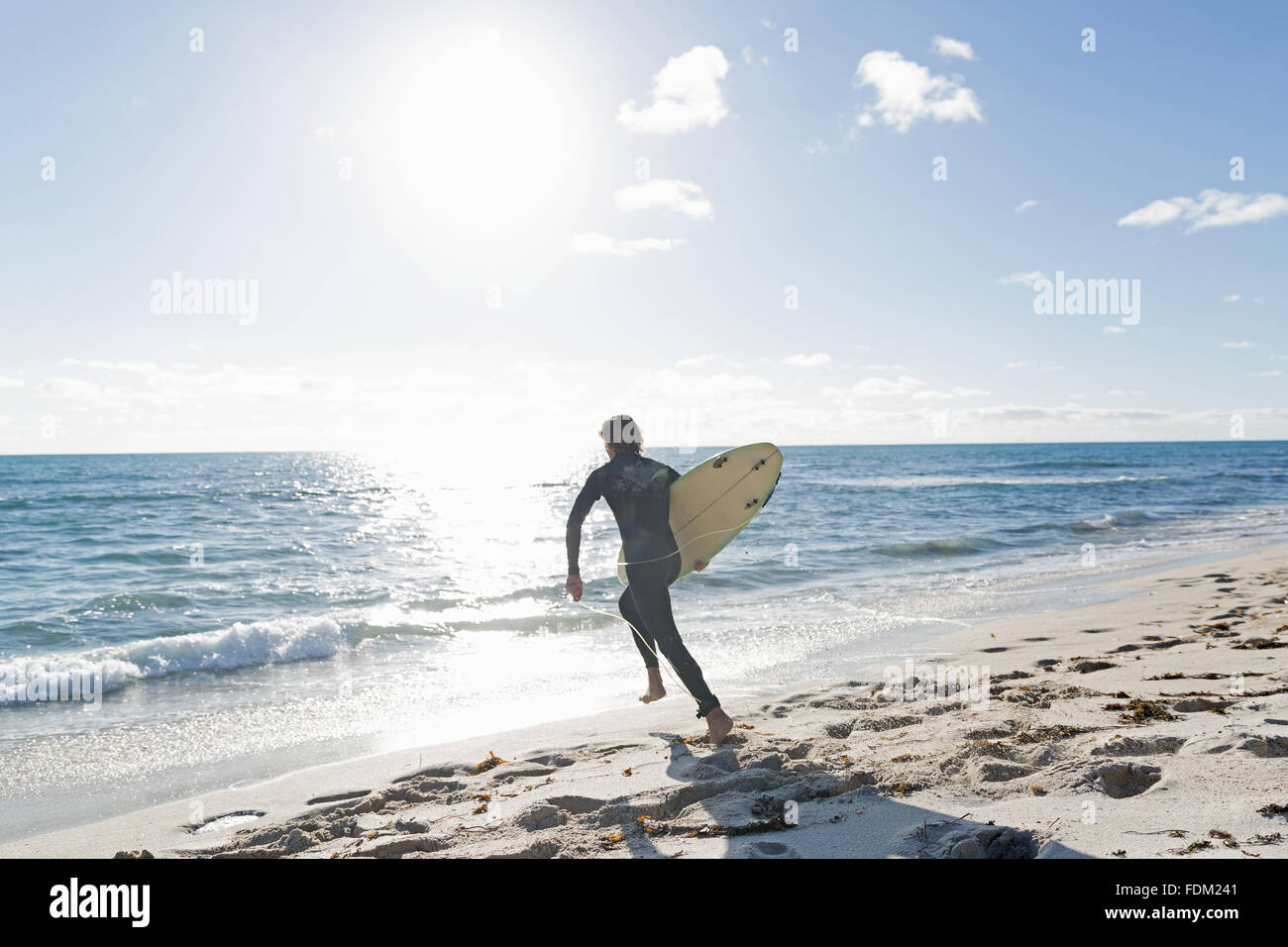 A surfer with his surfboard at the beach Stock Photo - Alamy