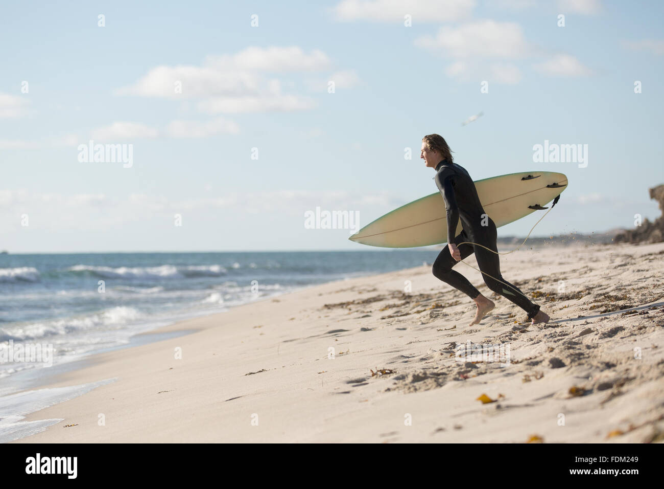 A surfer with his surfboard at the beach Stock Photo - Alamy