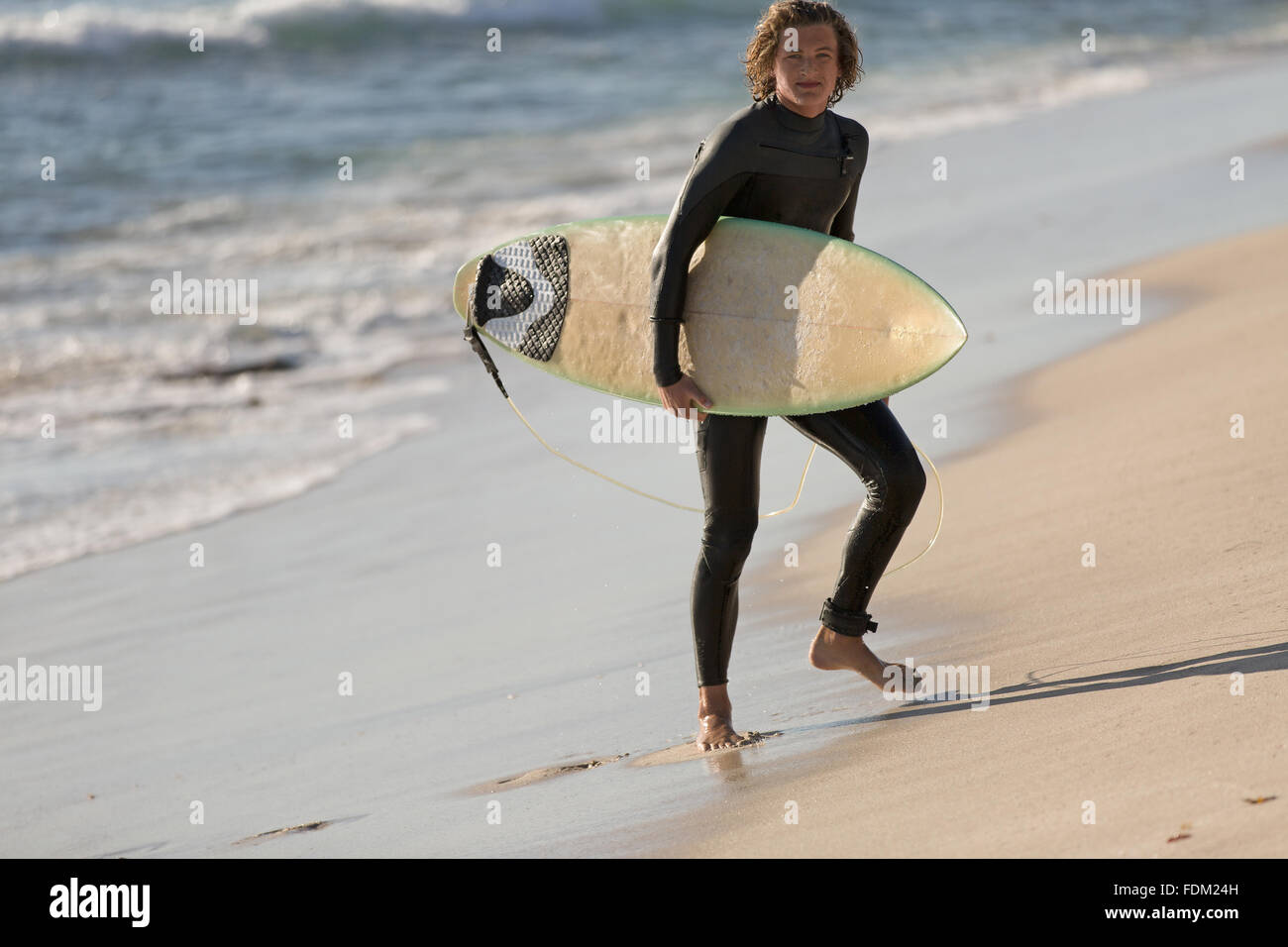 A surfer with his surfboard at the beach Stock Photo - Alamy