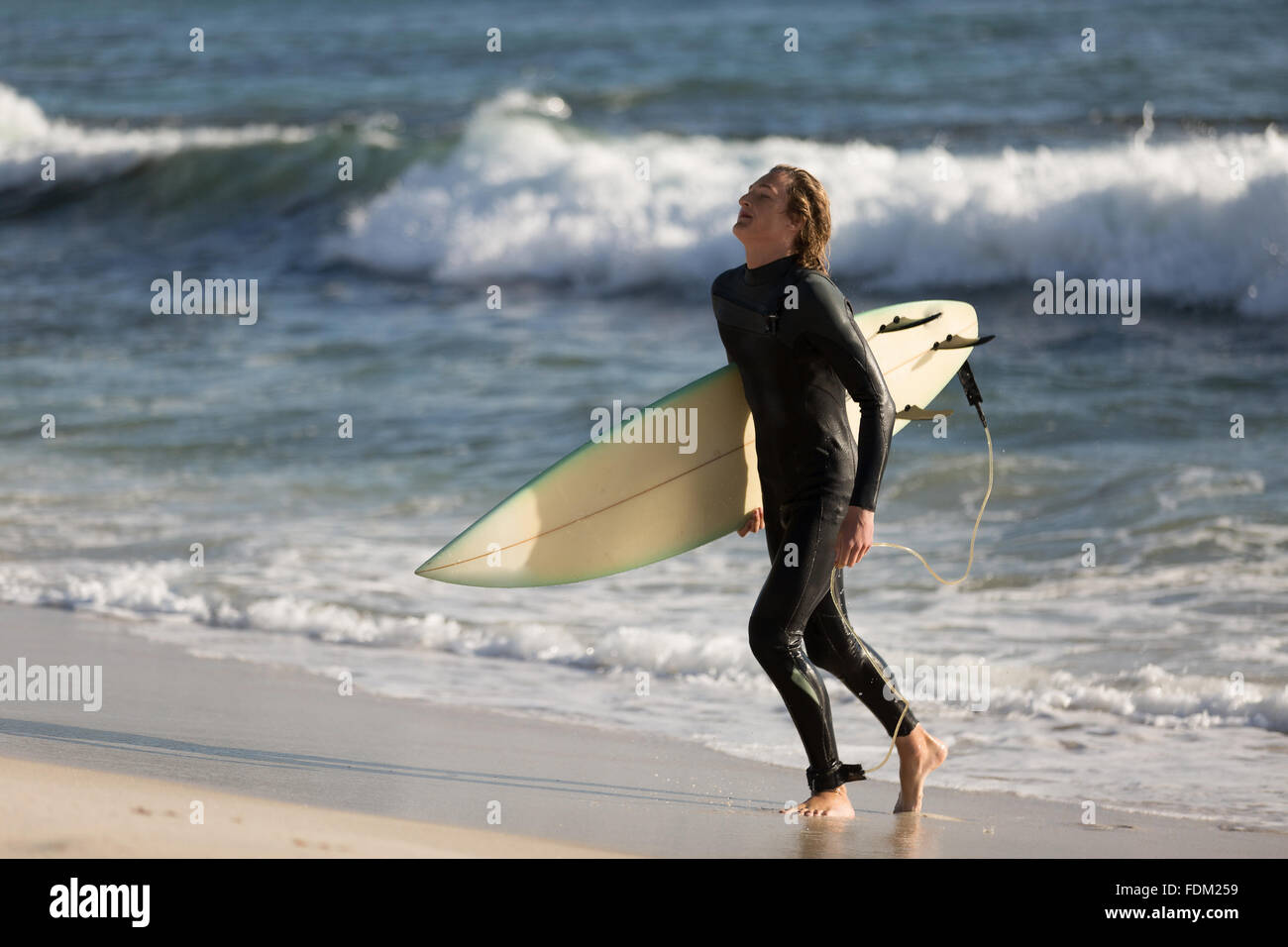 A surfer with his surfboard at the beach Stock Photo - Alamy