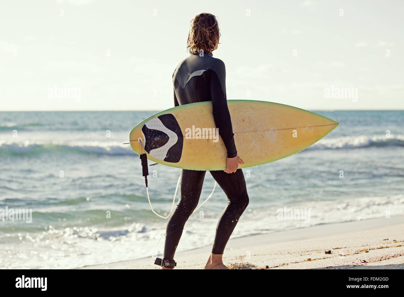 A surfer with his surfboard at the beach Stock Photo - Alamy