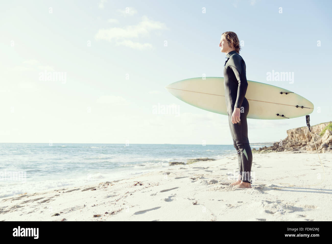 A surfer with his surfboard at the beach Stock Photo - Alamy