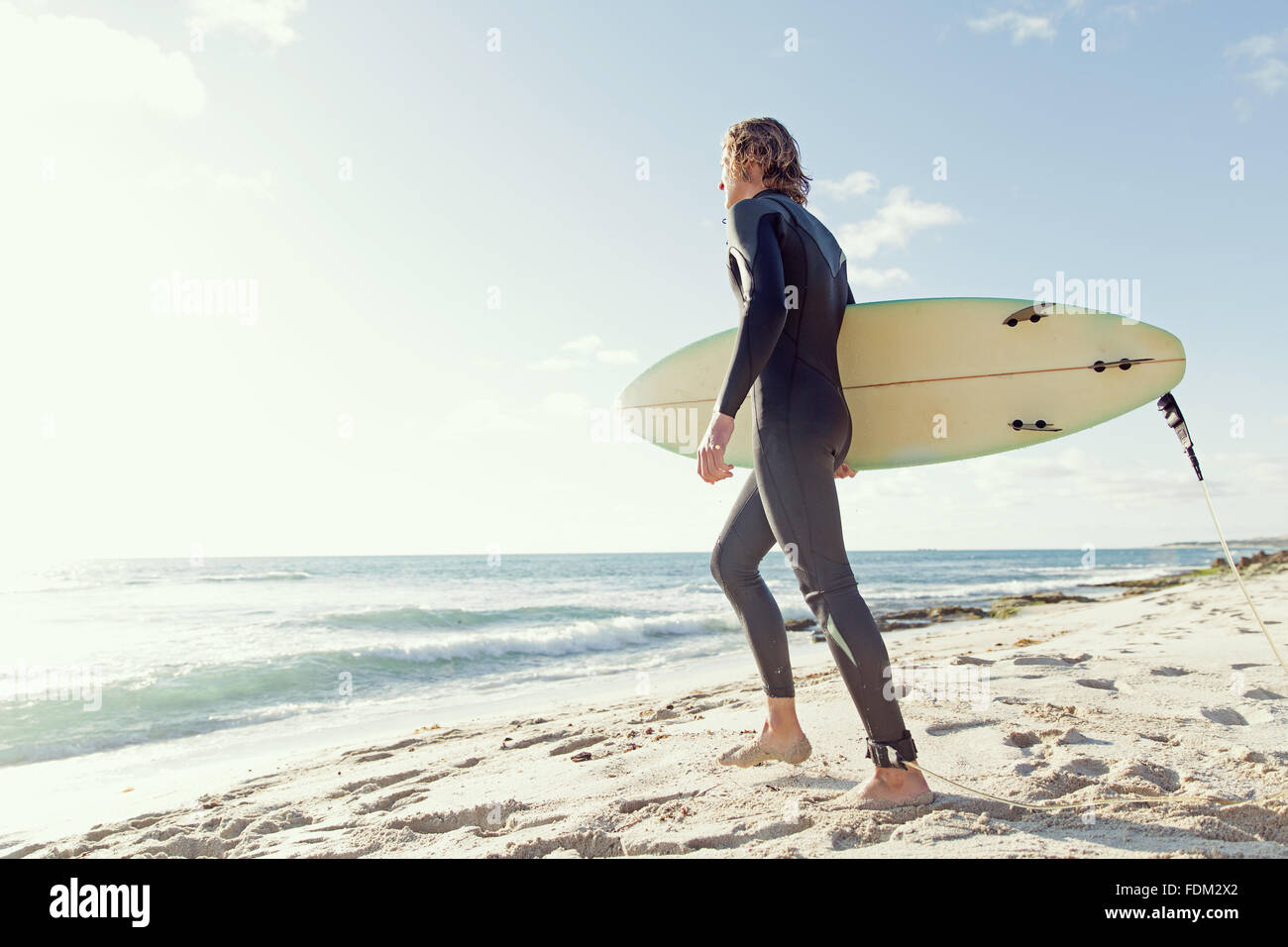 A surfer with his surfboard at the beach Stock Photo - Alamy