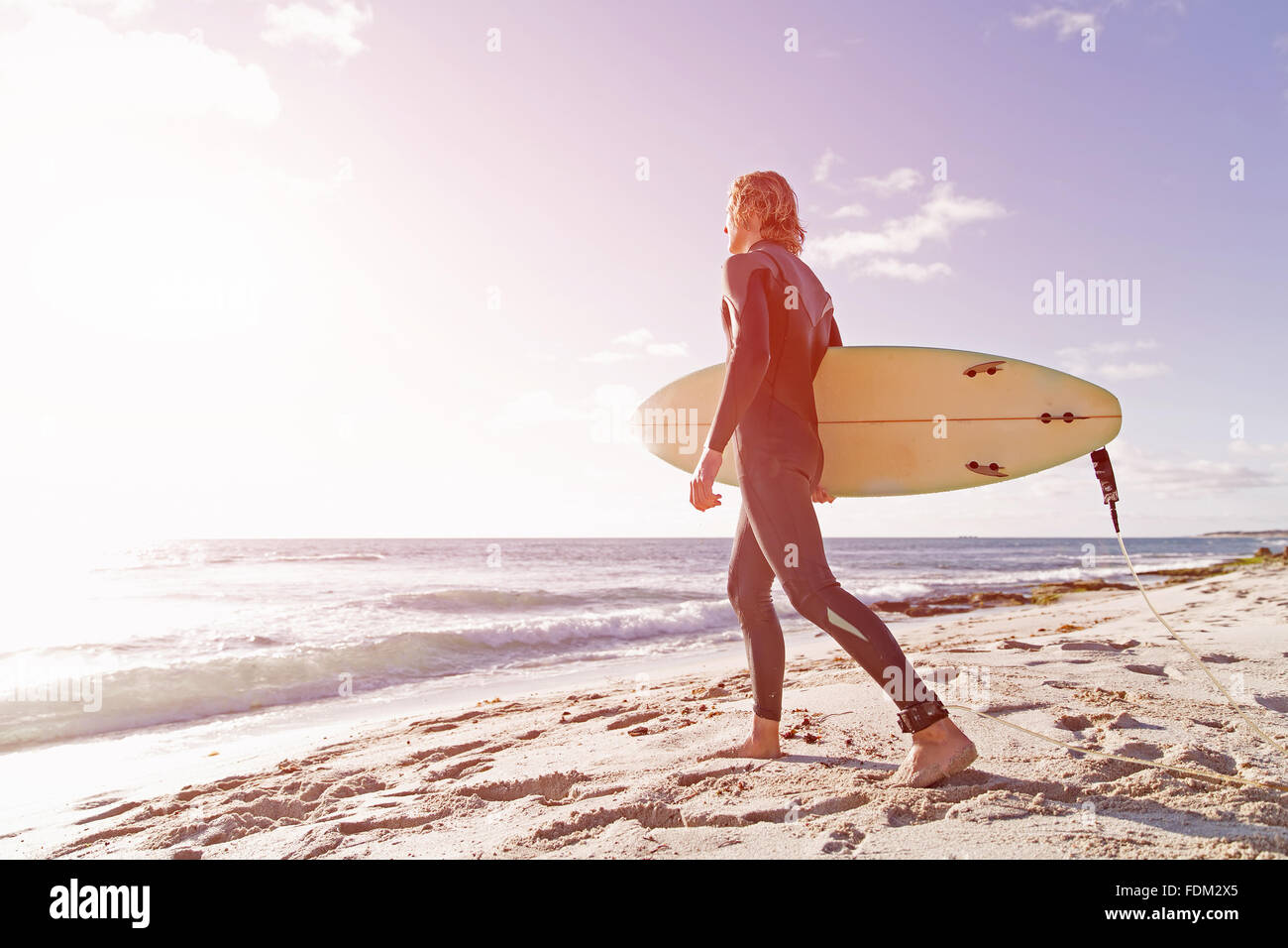 A surfer with his surfboard at the beach Stock Photo - Alamy