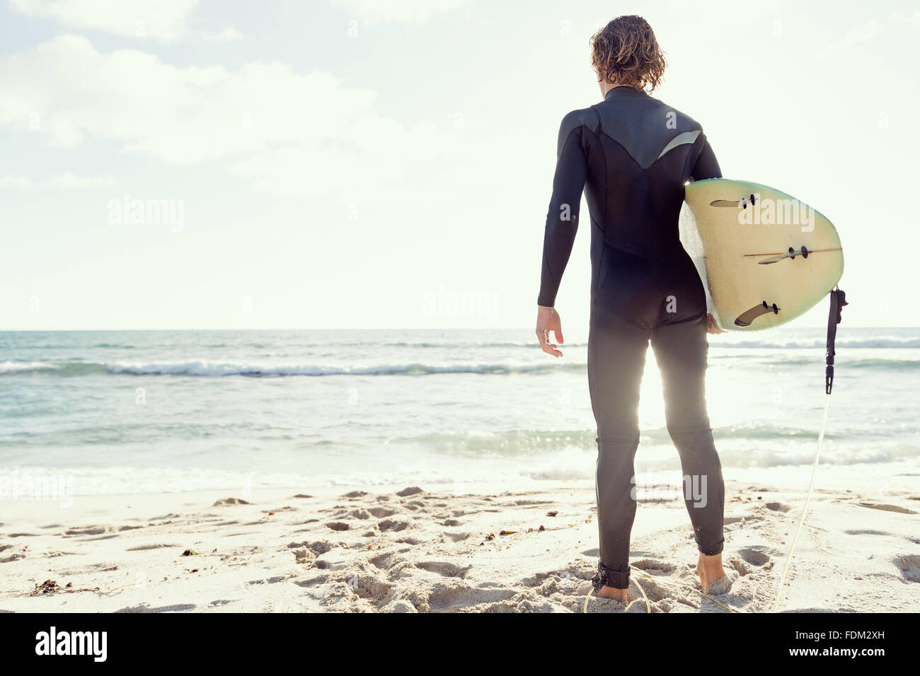 A surfer with his surfboard at the beach Stock Photo - Alamy