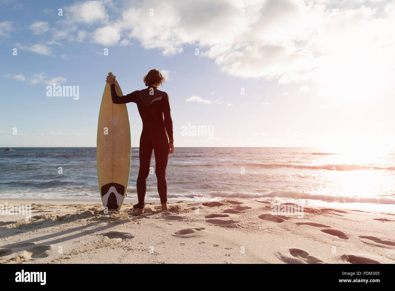 A surfer with his surfboard at the beach Stock Photo - Alamy