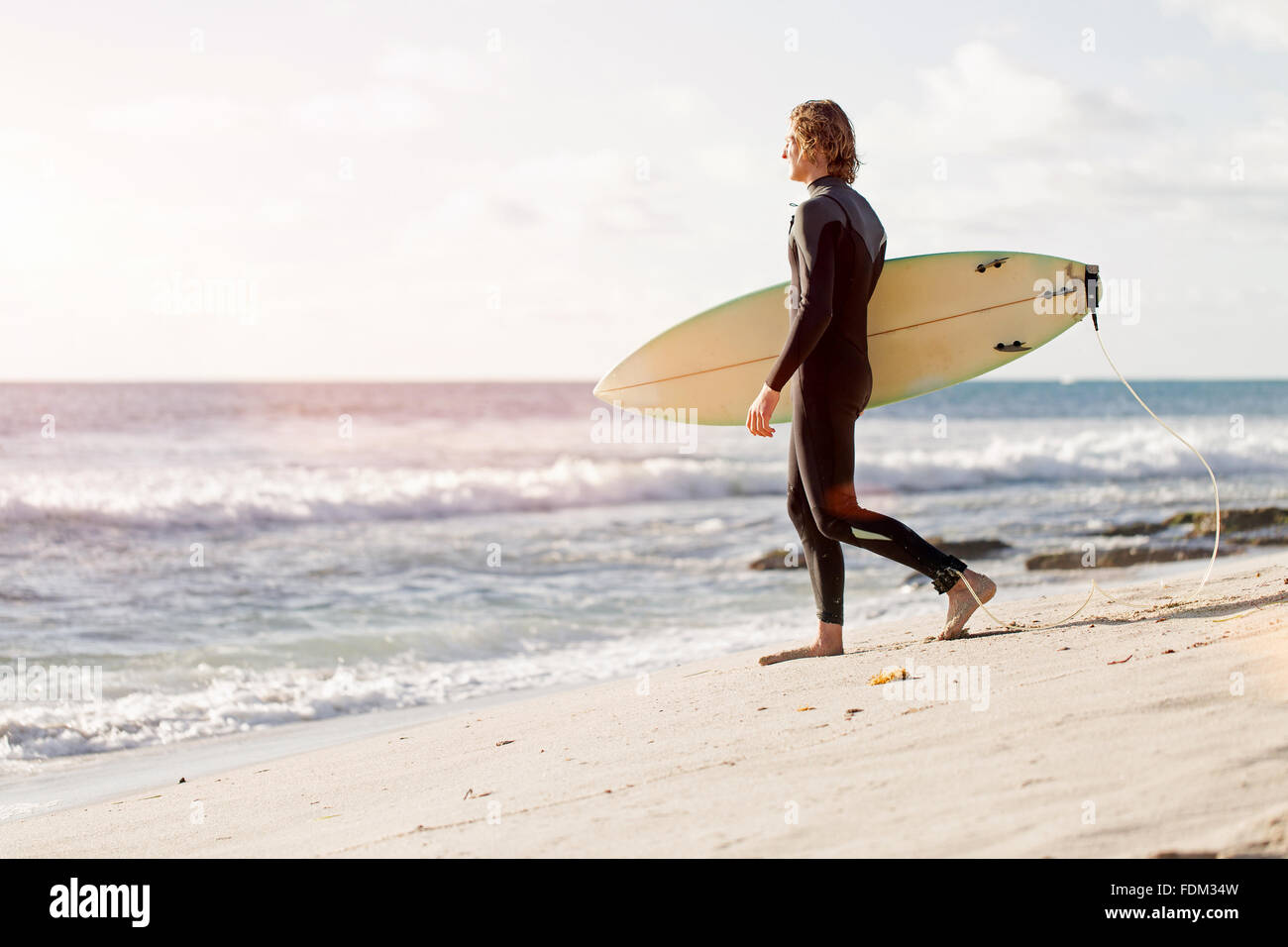 A surfer with his surfboard at the beach Stock Photo - Alamy