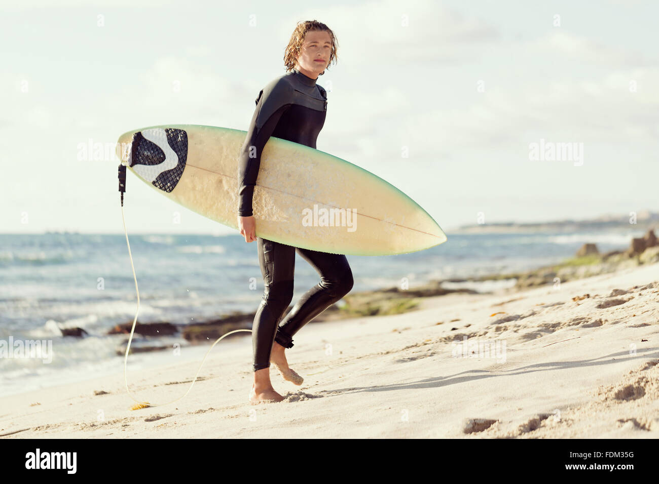 A surfer with his surfboard at the beach Stock Photo - Alamy