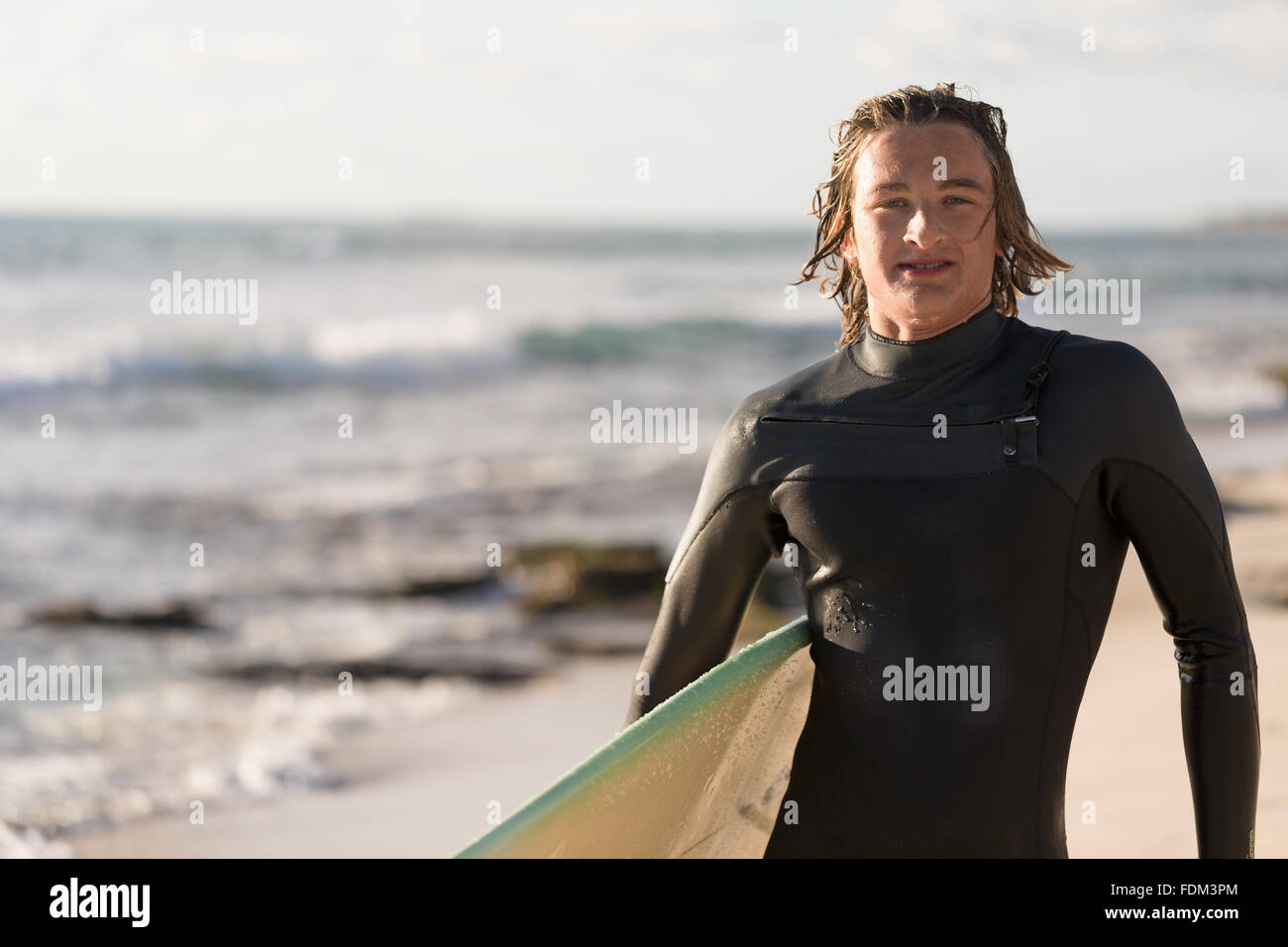 A surfer with his surfboard at the beach Stock Photo - Alamy