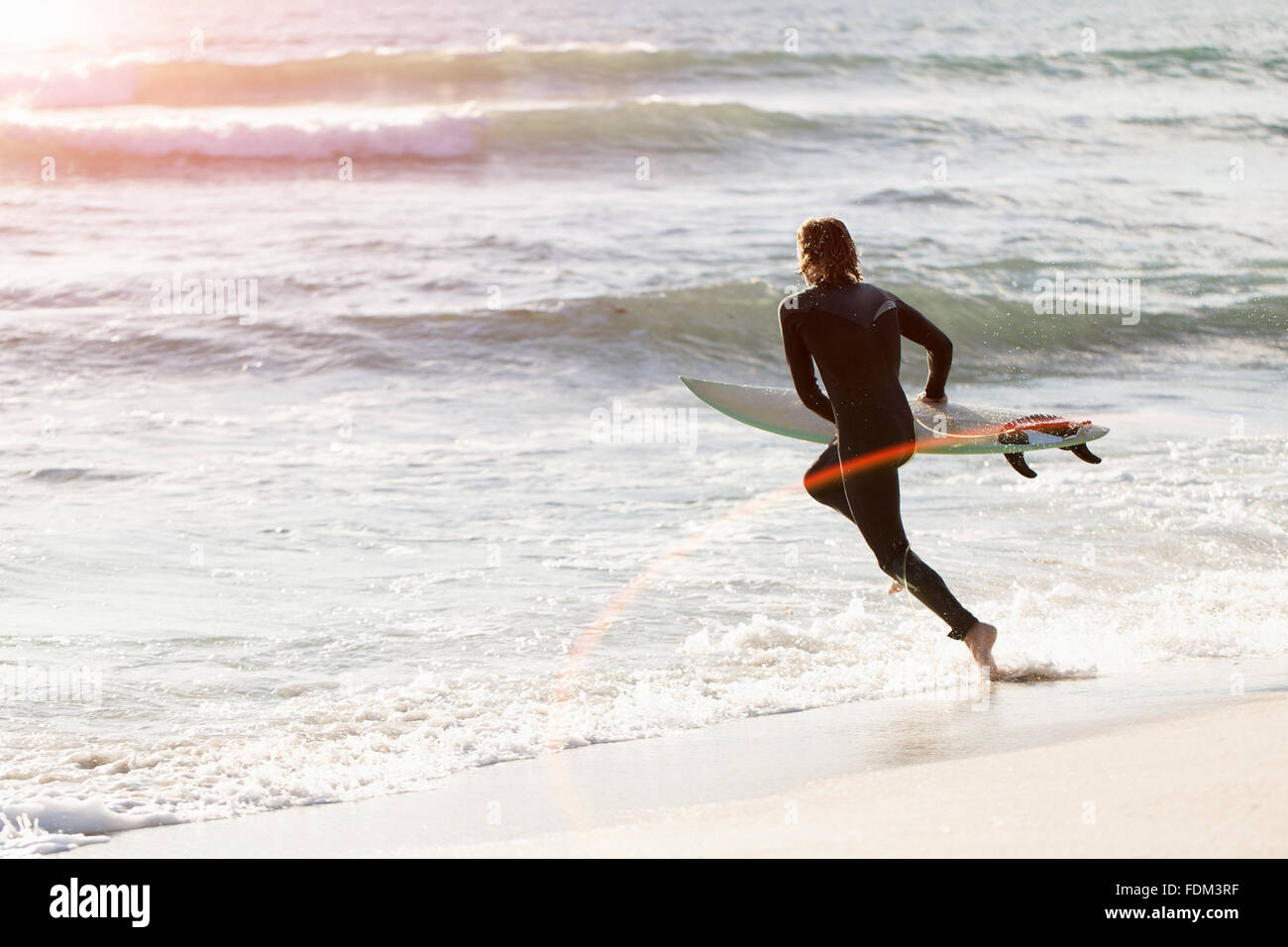 A surfer with his surfboard at the beach Stock Photo - Alamy