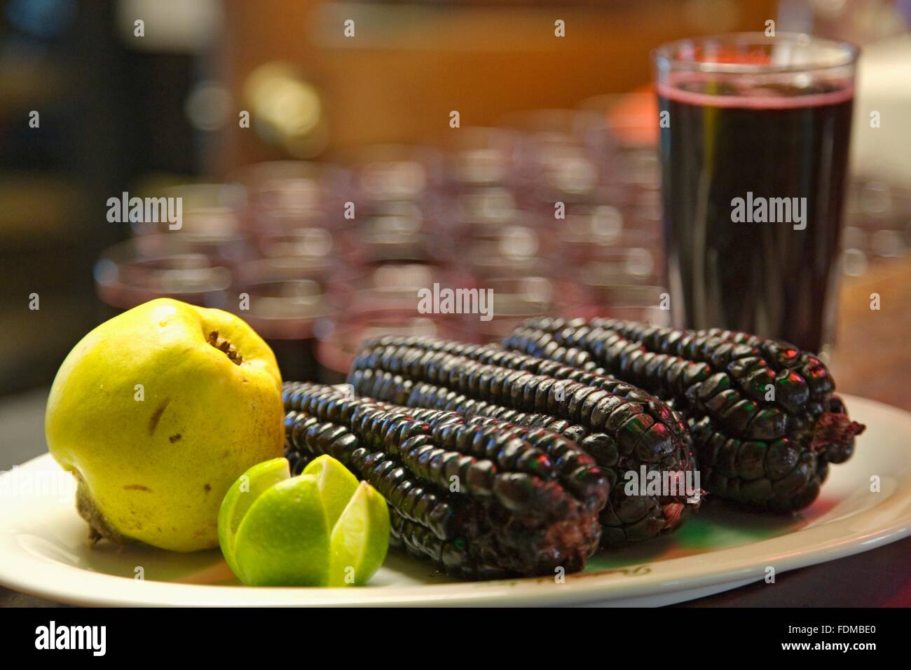 Peru, Lima, three purple maize corn cobs, a quince, and a sliced lime ...
