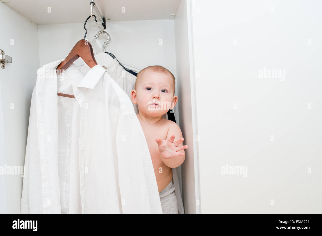 little child trying on clothes. He wants to dress white shirt Stock ...