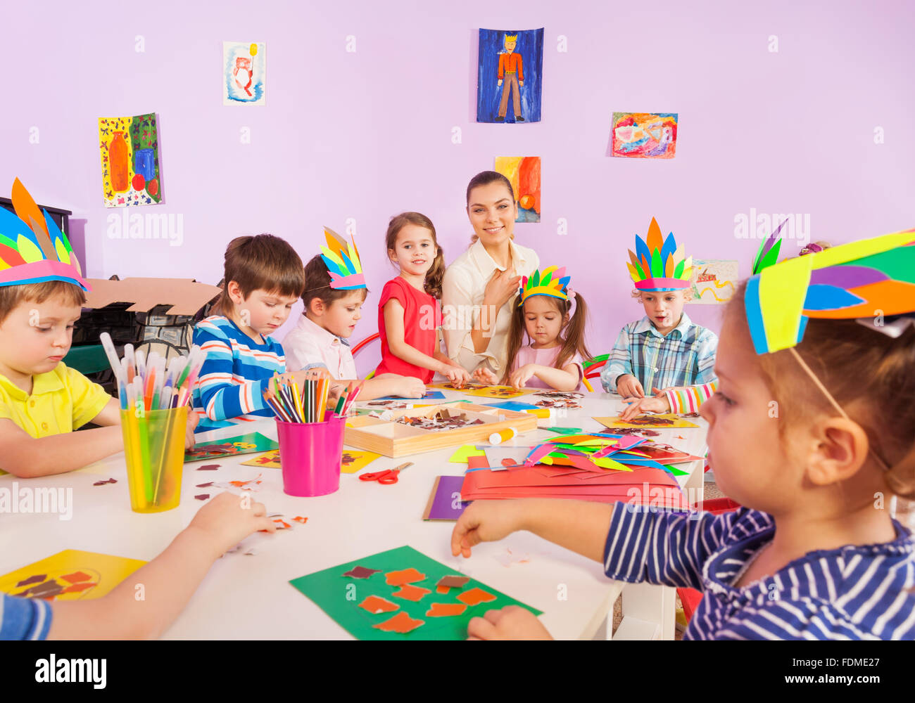 Children glue paper crafts together with teacher Stock Photo - Alamy