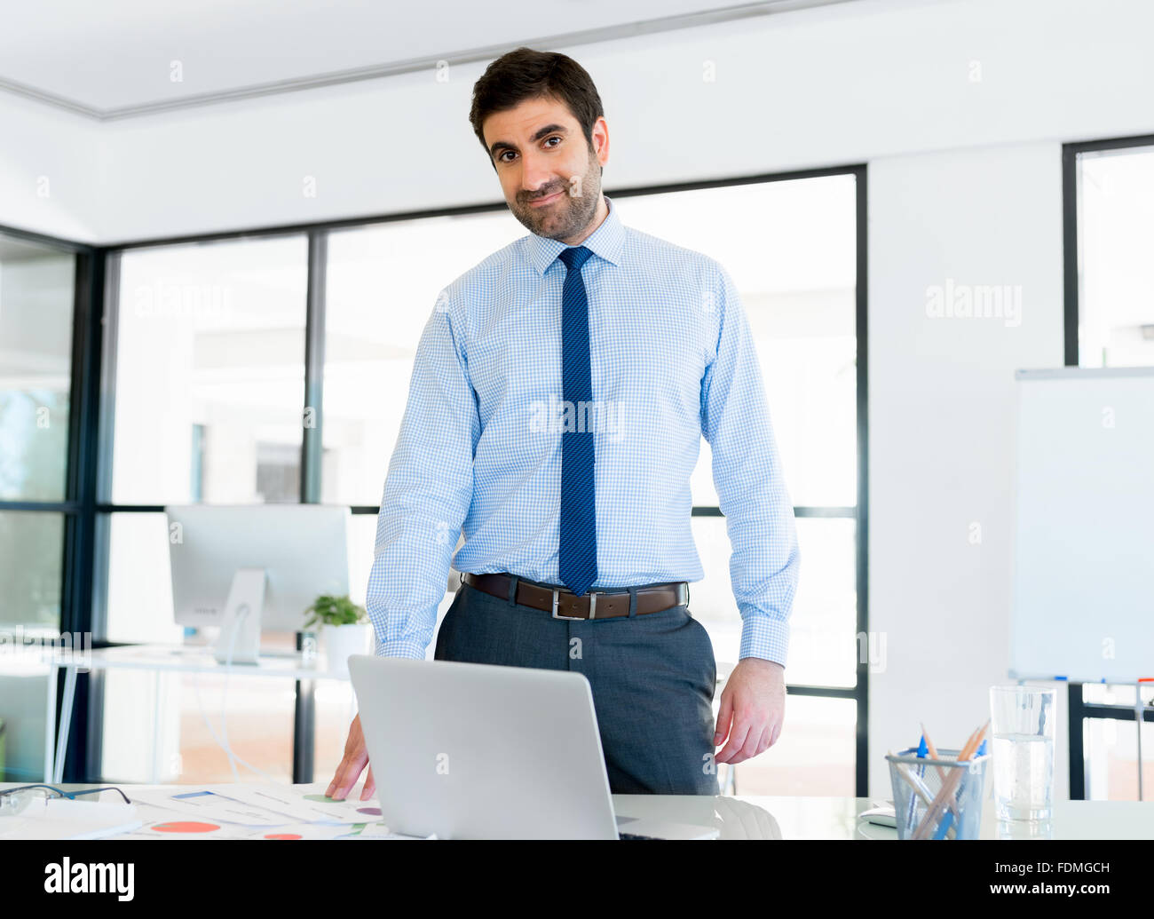 Young businessman in office standing and smiling Stock Photo - Alamy