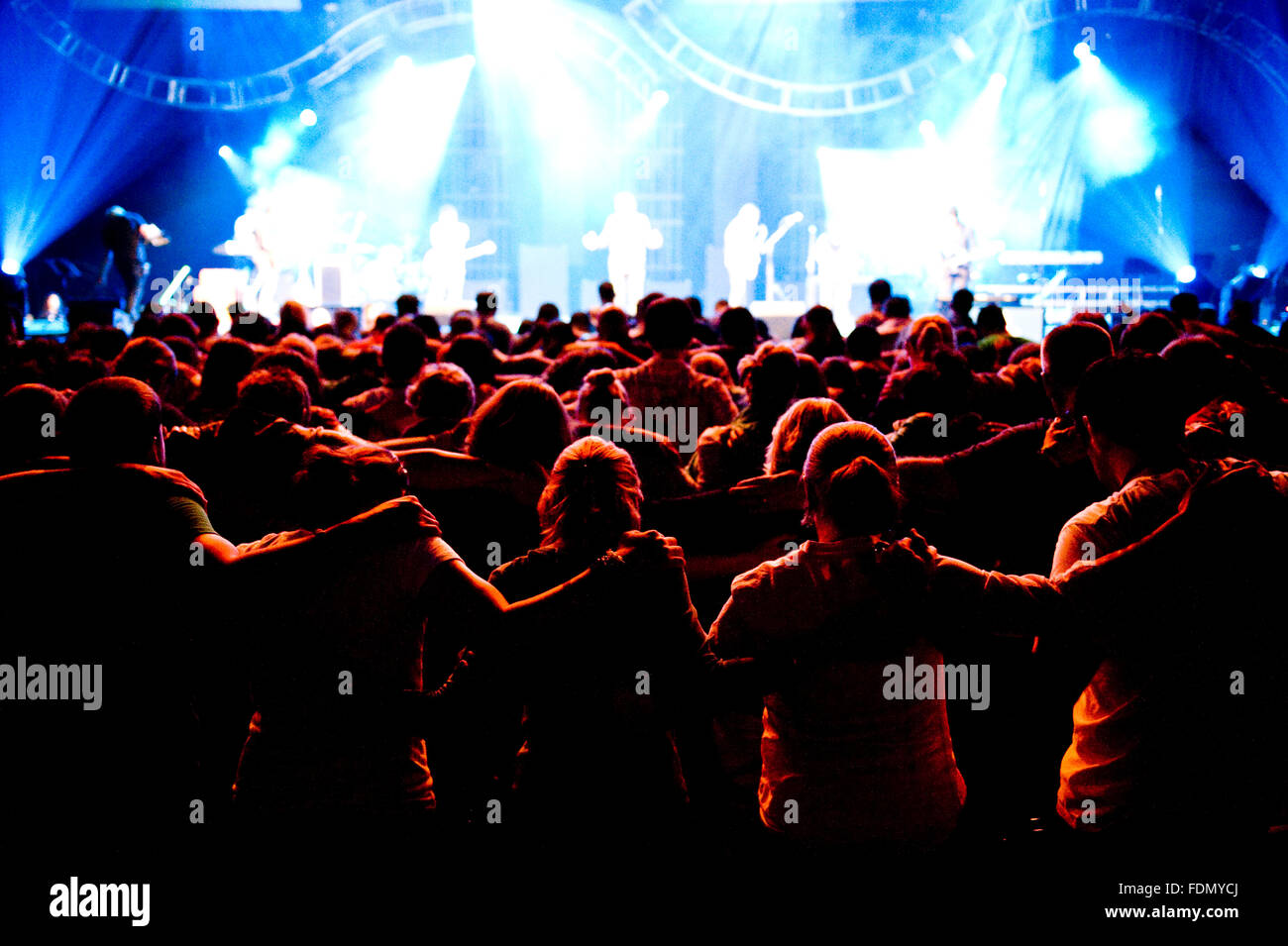 Audience at a concert with brightly colored background on a stage ...