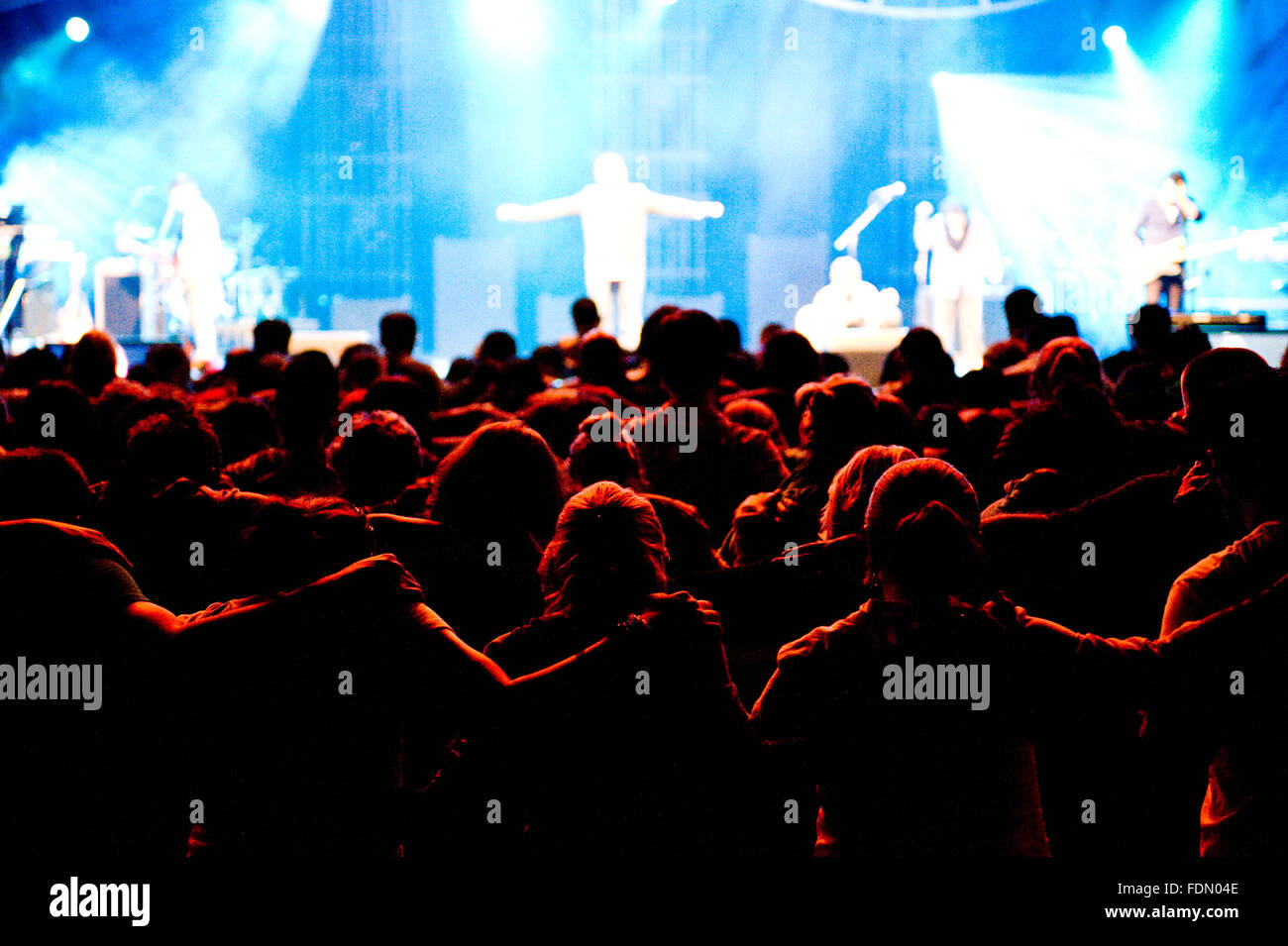 Audience at a concert with brightly colored background on a stage ...