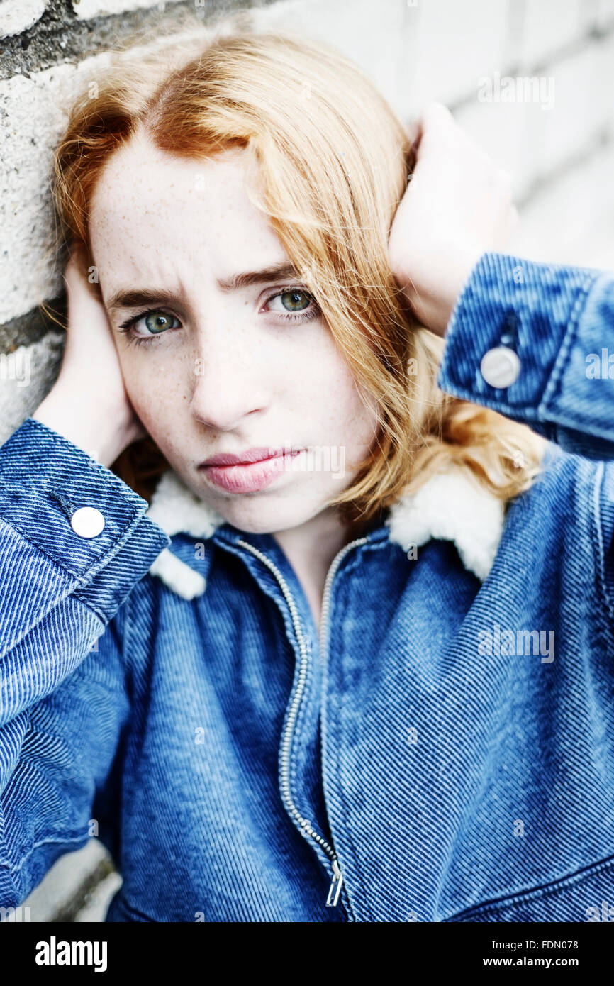 Timid girl, red-haired, putting her hands over her ears, portrait ...
