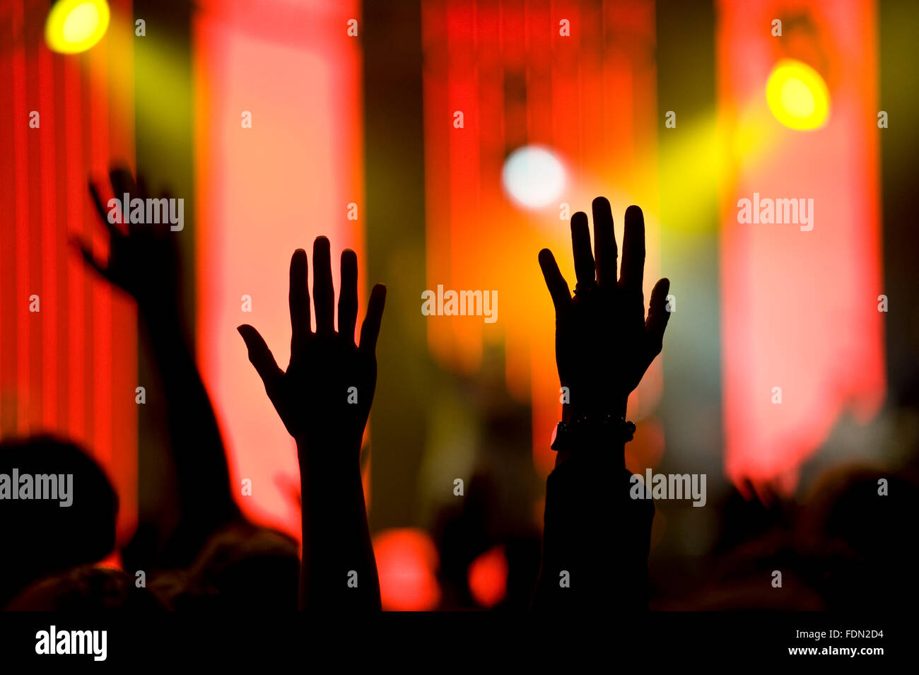 Audience raises hands in the air at a concert with brightly colored ...