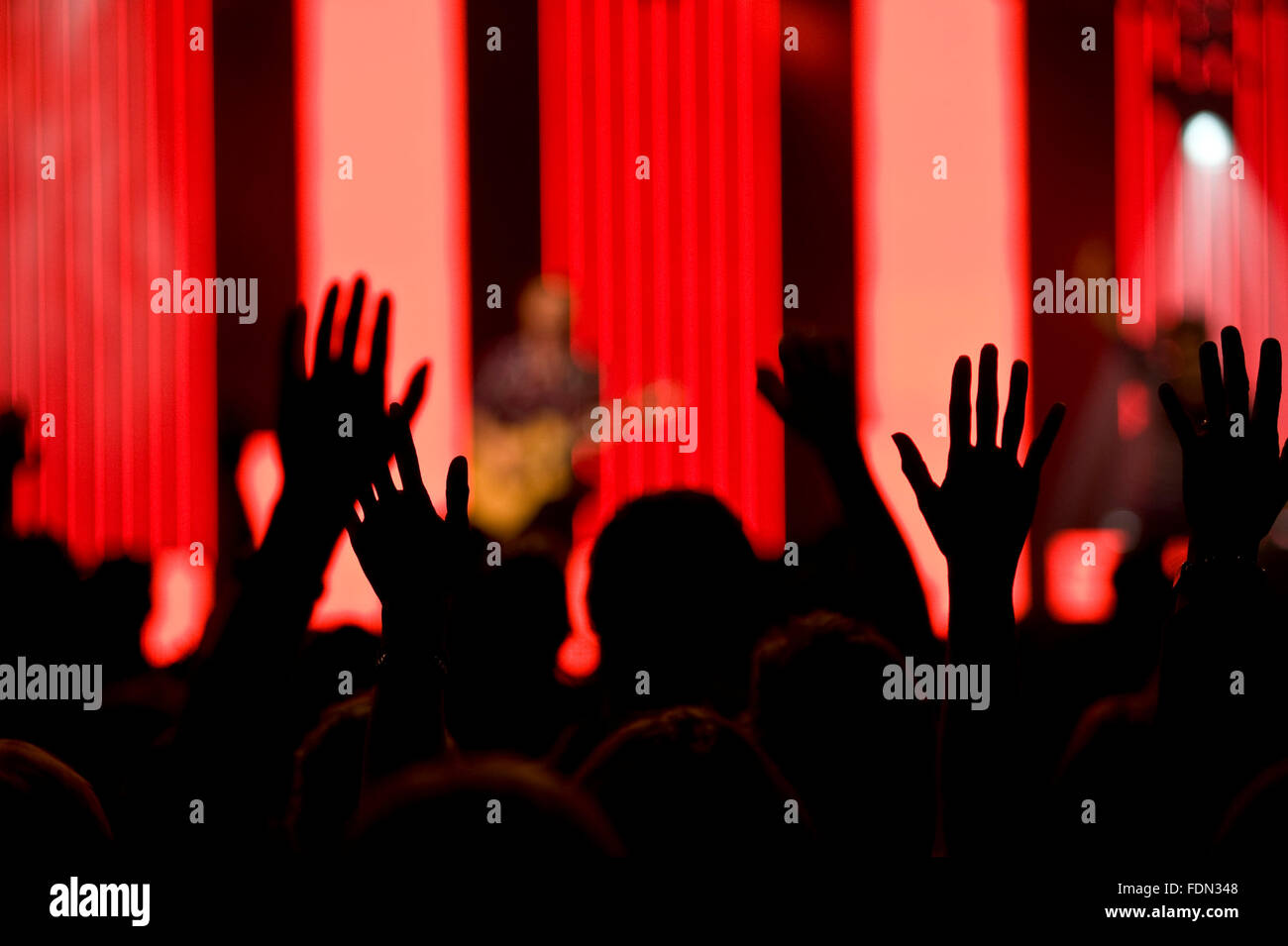 Audience raises hands in the air at a concert with brightly colored ...