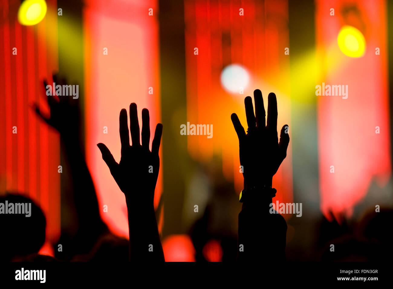 Worshipers raise their silhouetted hands against a colorful background ...