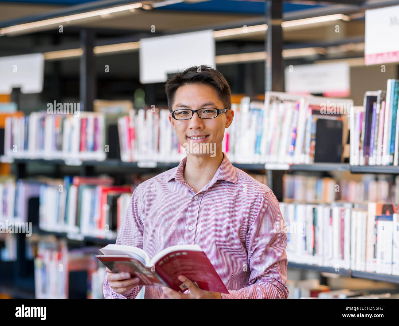 Happy male asian student holding books at the library Stock Photo - Alamy
