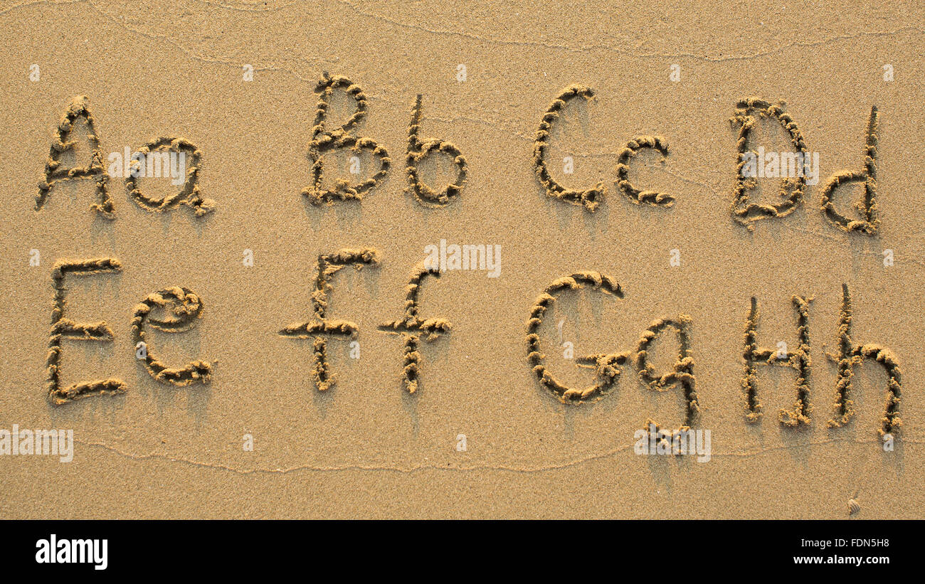 Letters of the alphabet written on sandy beach (from A to H Stock Photo ...