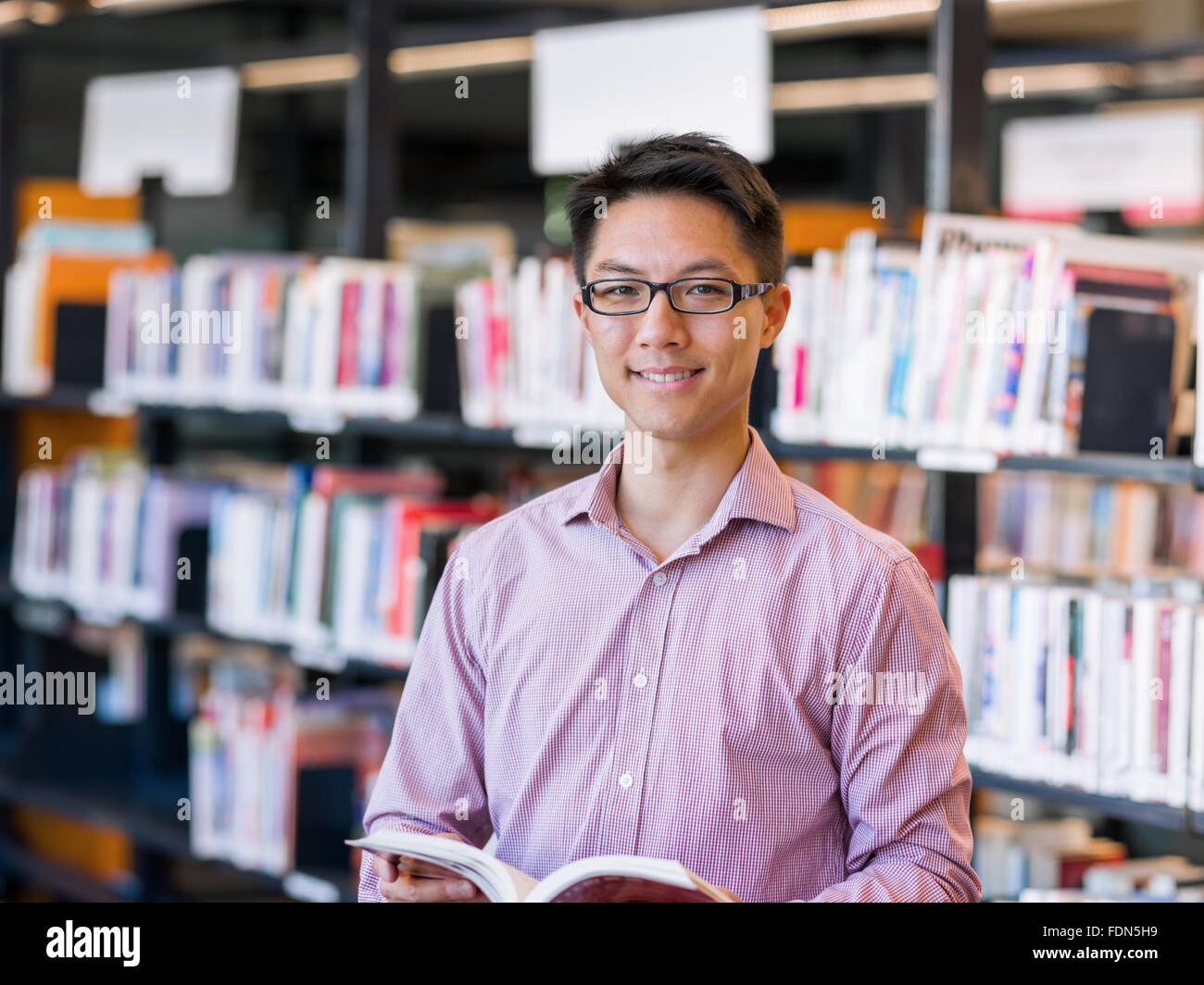 Happy male asian student holding books at the library Stock Photo - Alamy