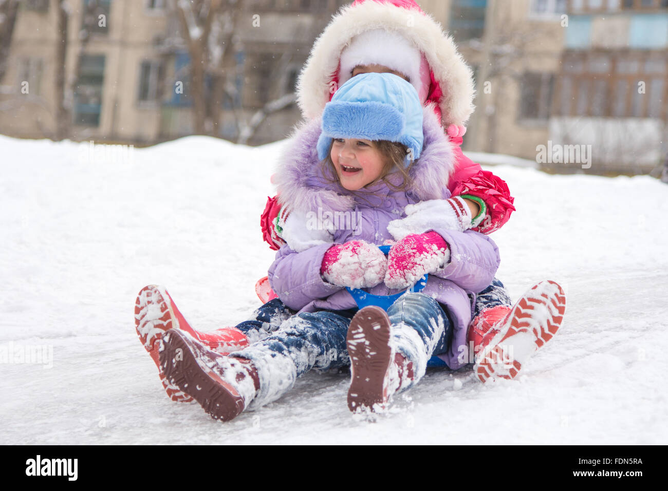 Two girls having fun rolling down the ice slide Stock Photo - Alamy