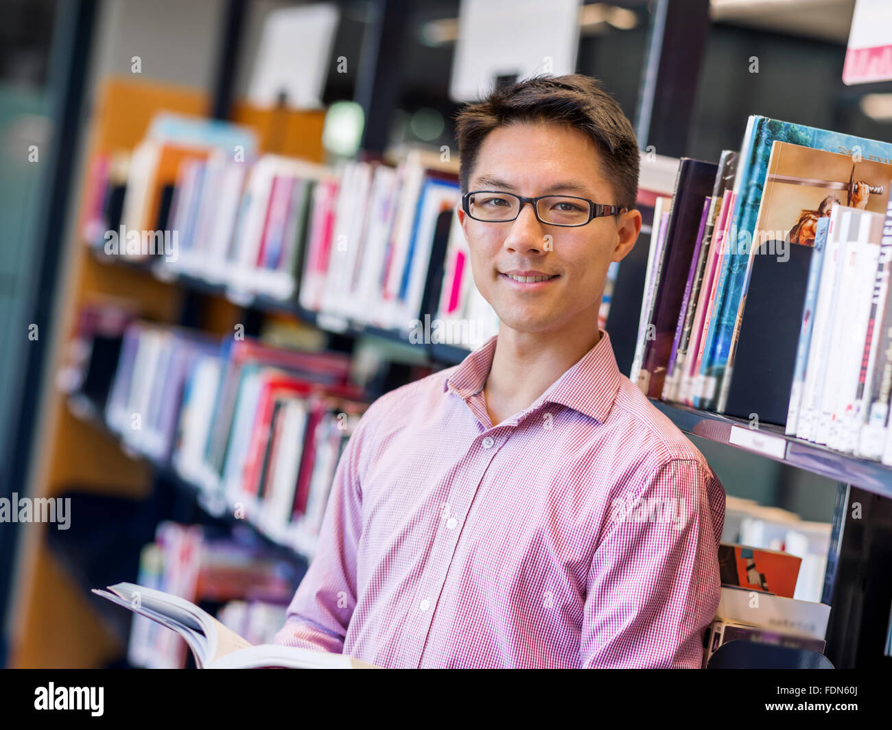 Happy male asian student holding books at the library Stock Photo - Alamy