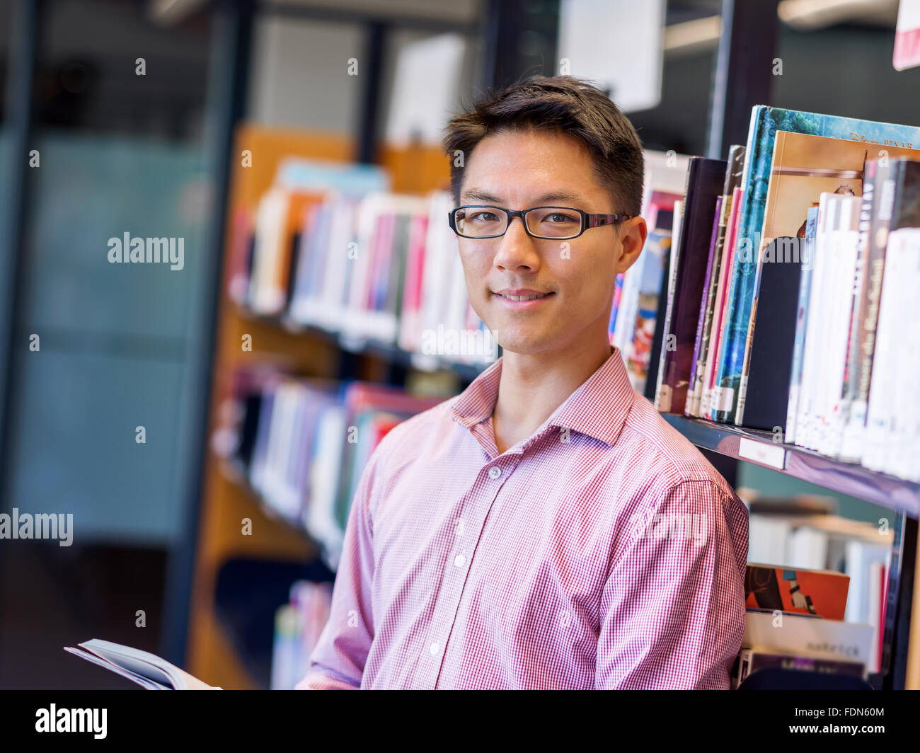 Happy male asian student holding books at the library Stock Photo - Alamy