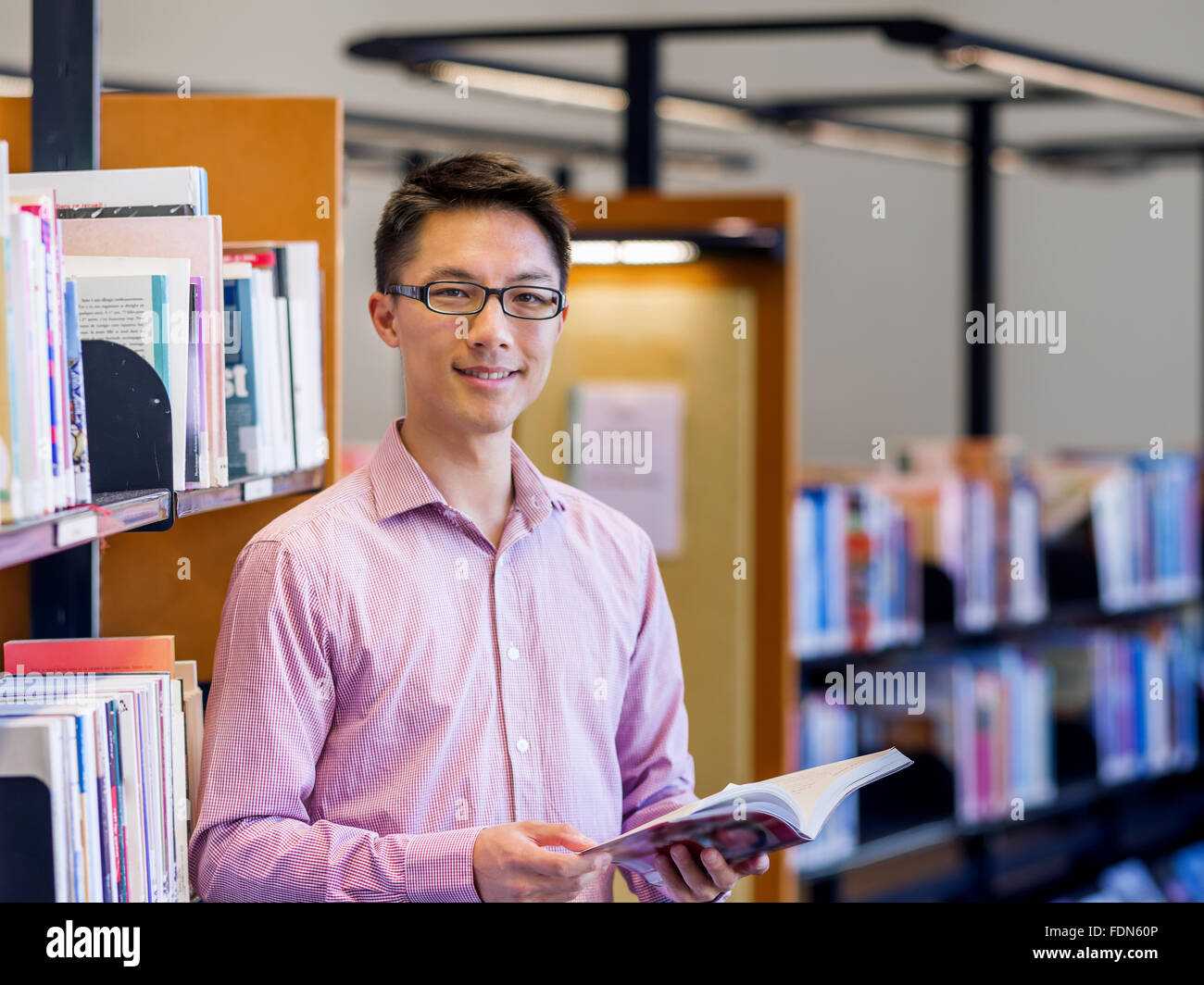 Happy male asian student holding books at the library Stock Photo - Alamy