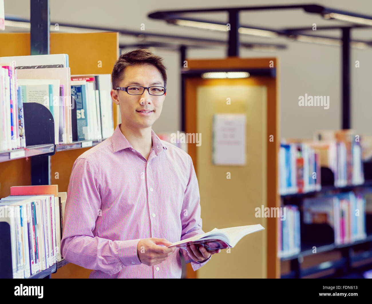Happy male asian student holding books at the library Stock Photo - Alamy