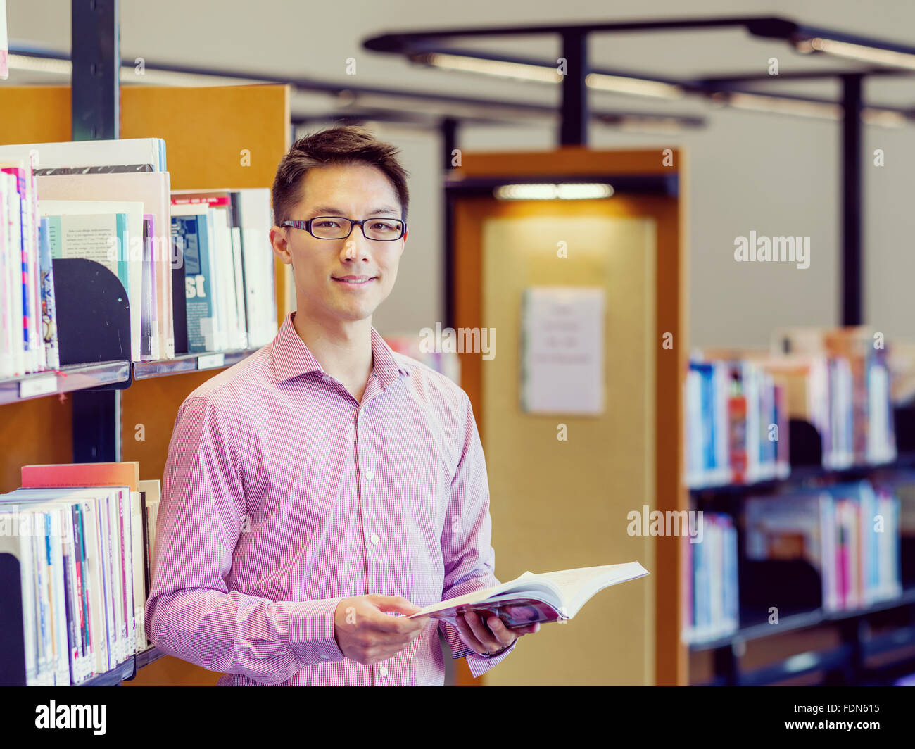 Happy male asian student holding books at the library Stock Photo - Alamy