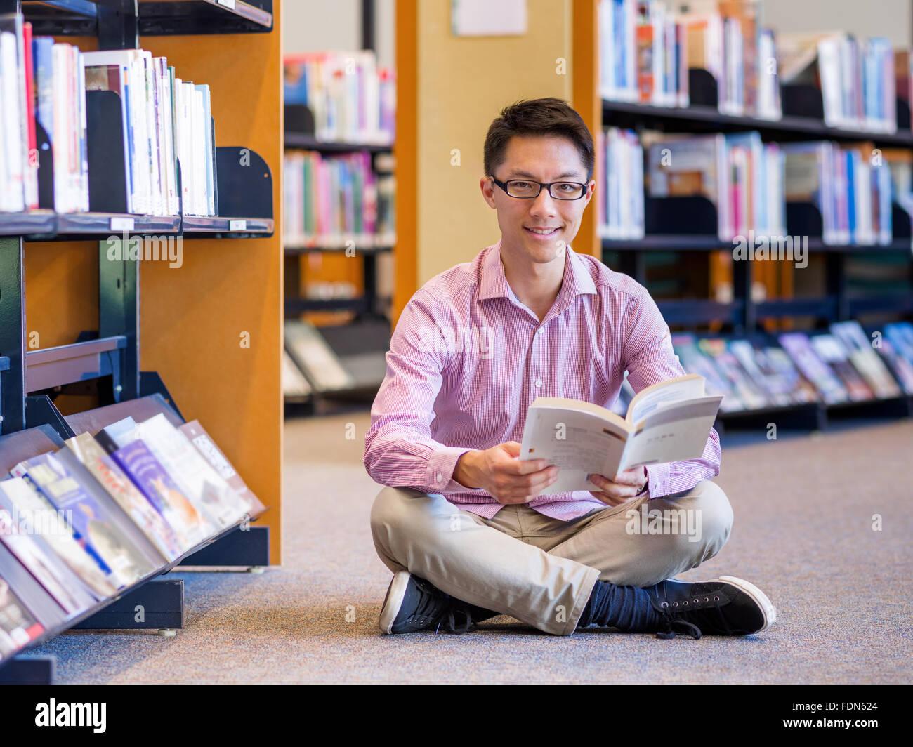 Happy male asian student holding books at the library Stock Photo - Alamy