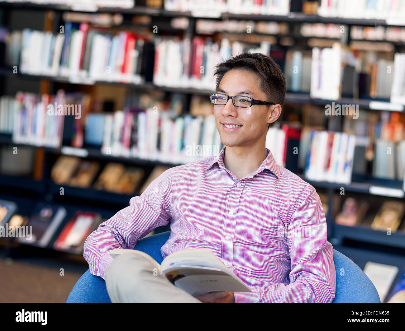 Happy male asian student holding books at the library Stock Photo - Alamy