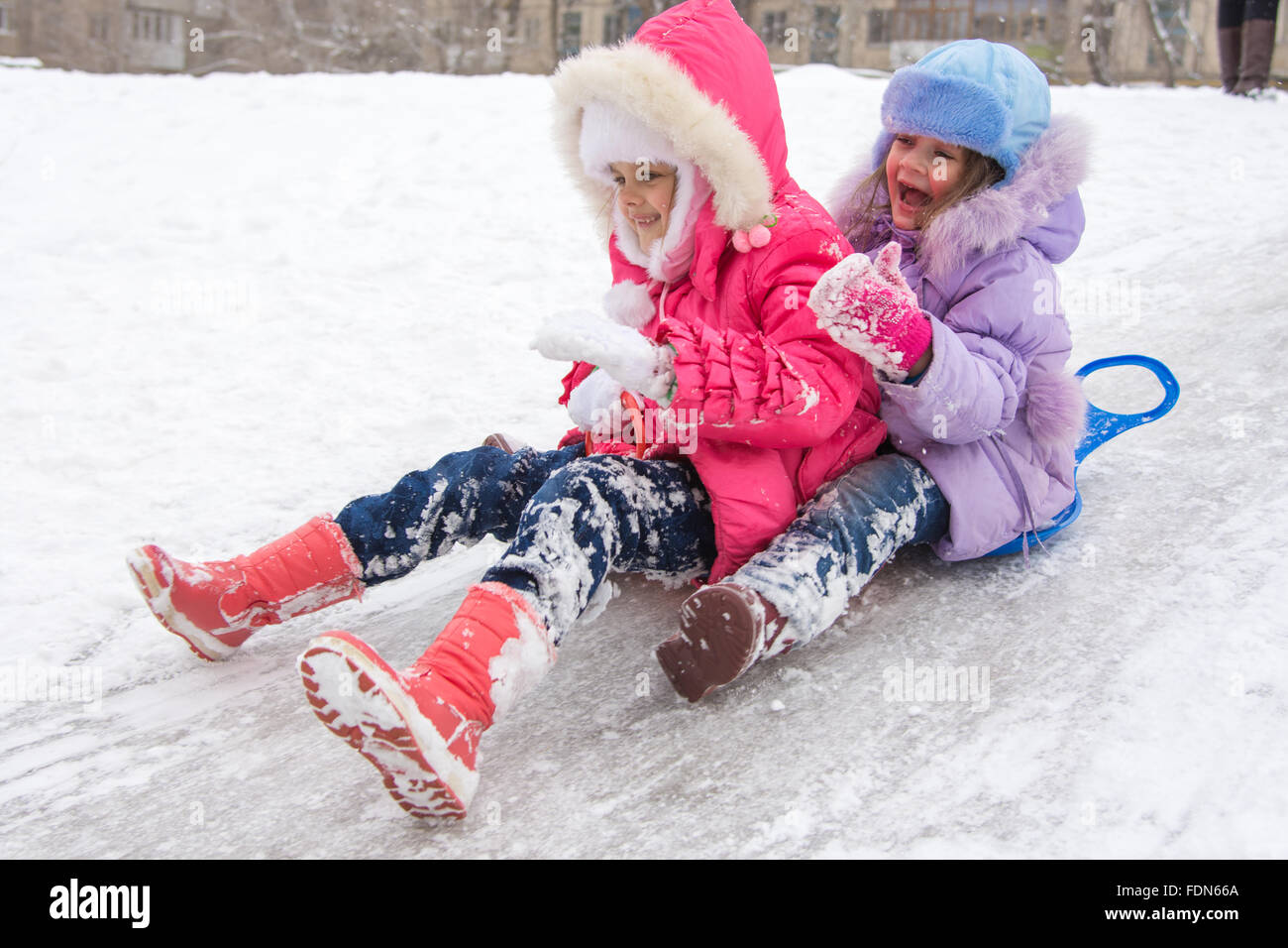 Two girls having fun rolling down the ice slide Stock Photo - Alamy