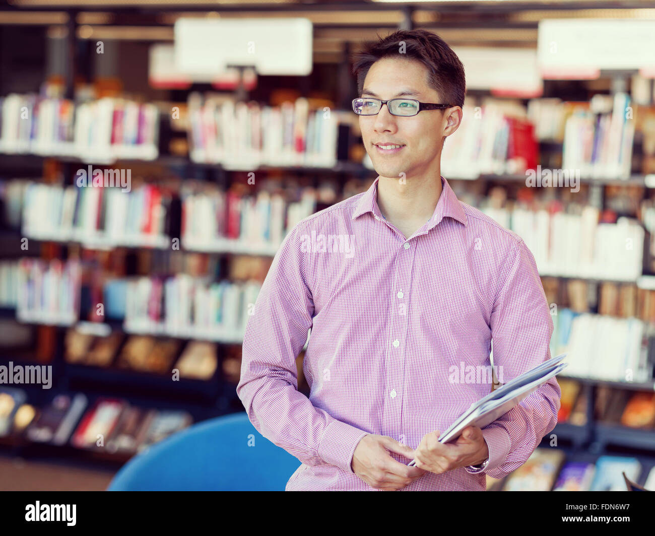 Happy male asian student holding books at the library Stock Photo - Alamy
