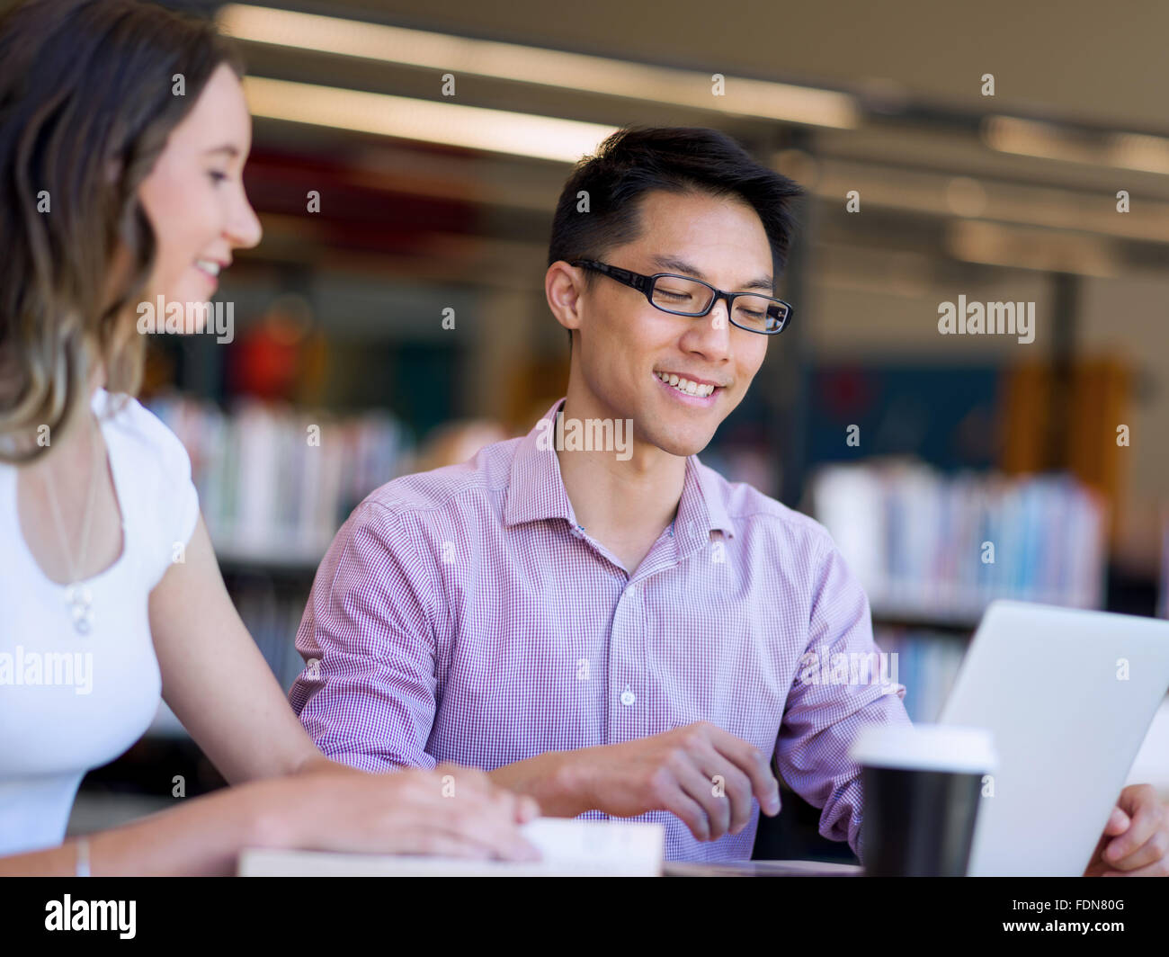 Two young students working together at the library Stock Photo - Alamy
