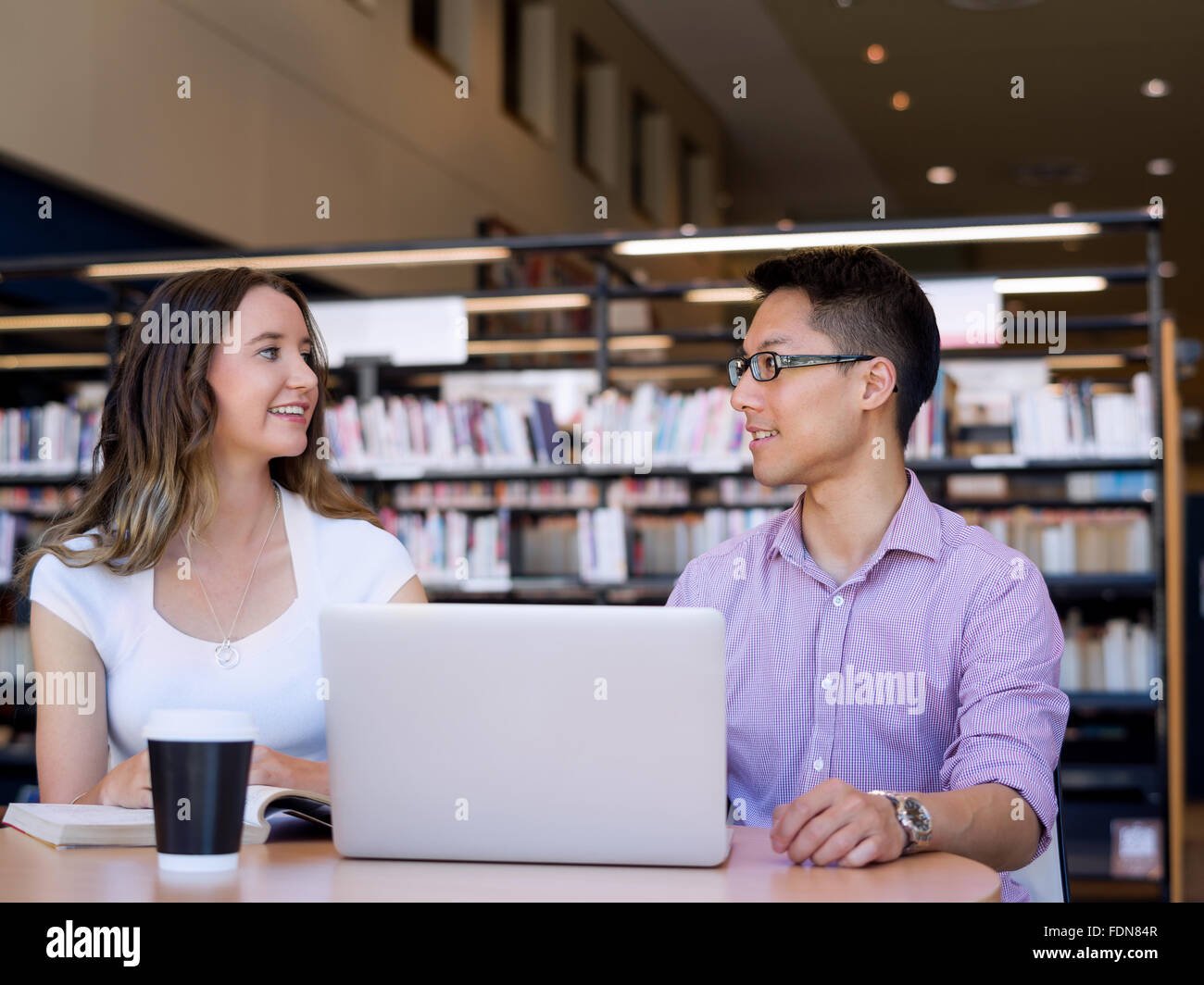 Two young students working together at the library Stock Photo - Alamy