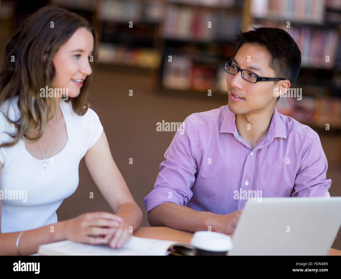 Two young students working together at the library Stock Photo - Alamy