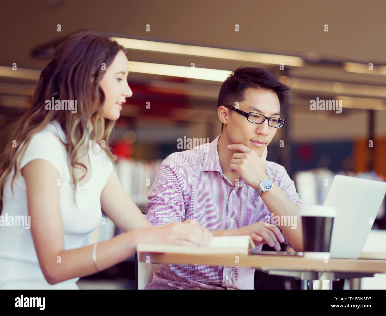 Two young students working together at the library Stock Photo - Alamy