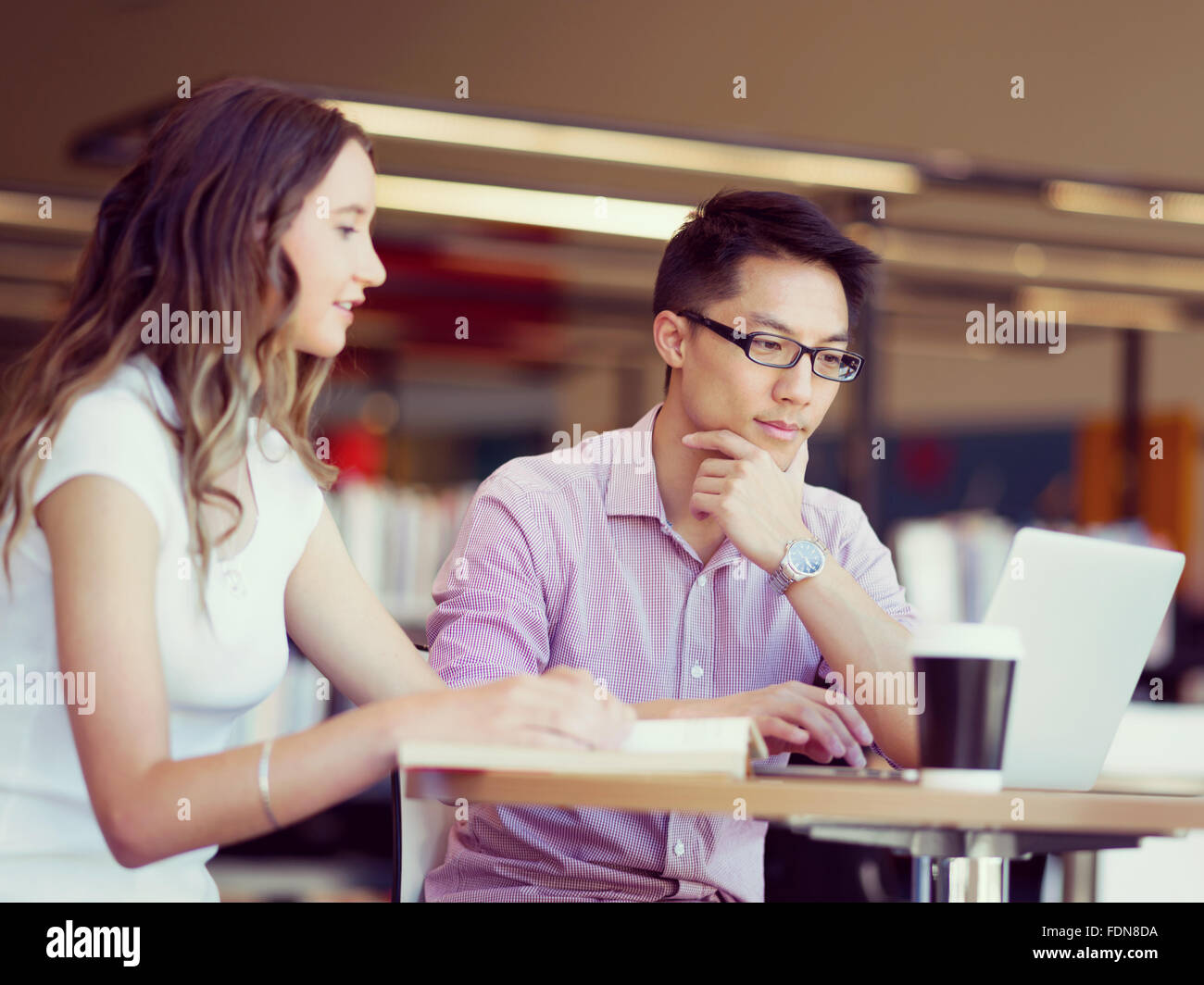Two young students working together at the library Stock Photo - Alamy