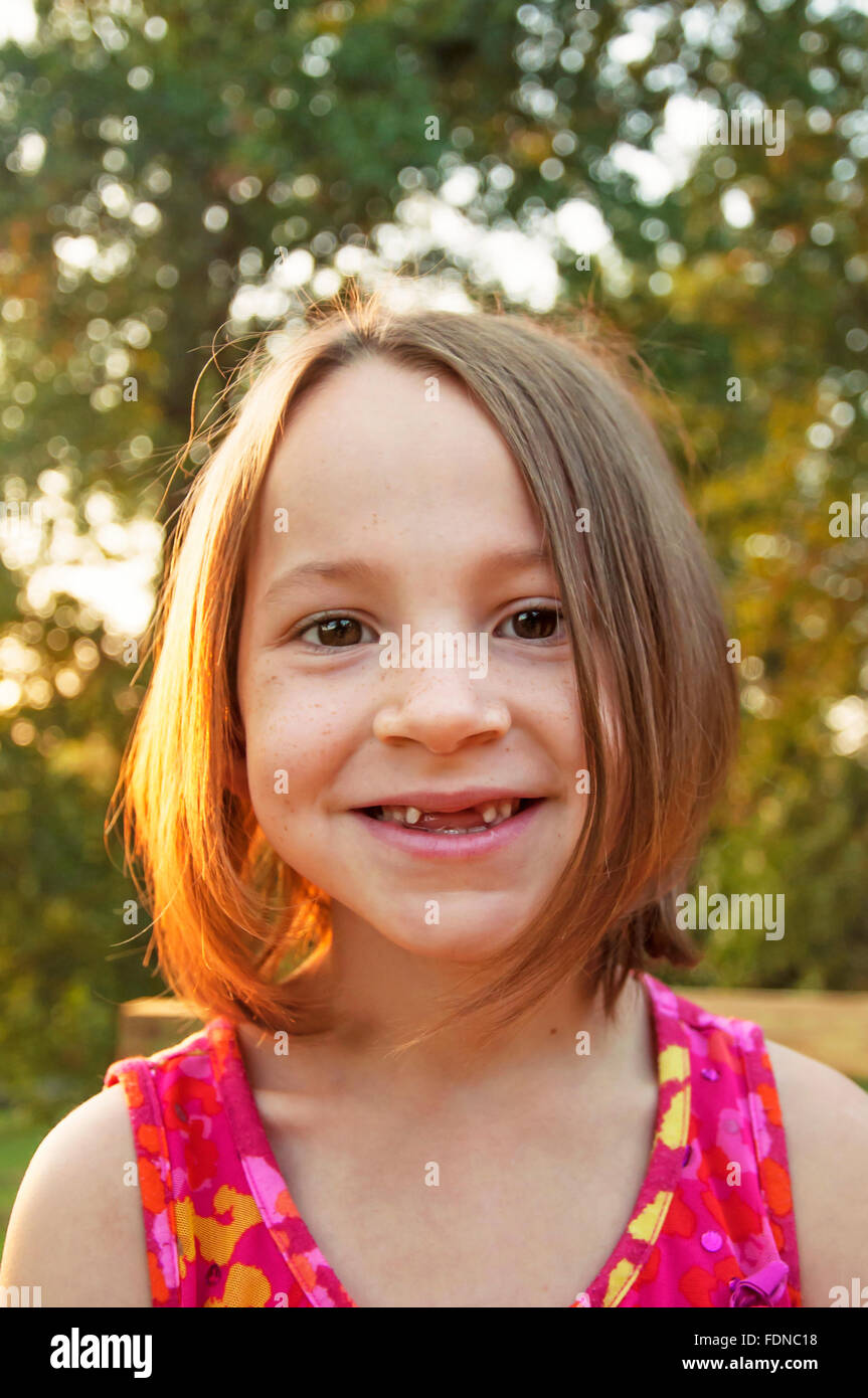 Cute little girl with missing teeth playing with yellow fallen leaves ...
