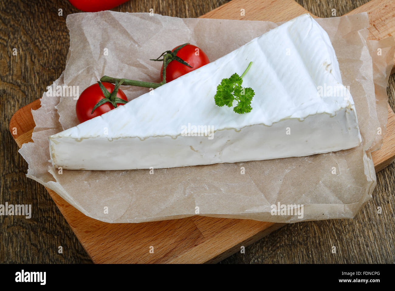 Brie cheese triangle with tomato and parsley Stock Photo - Alamy