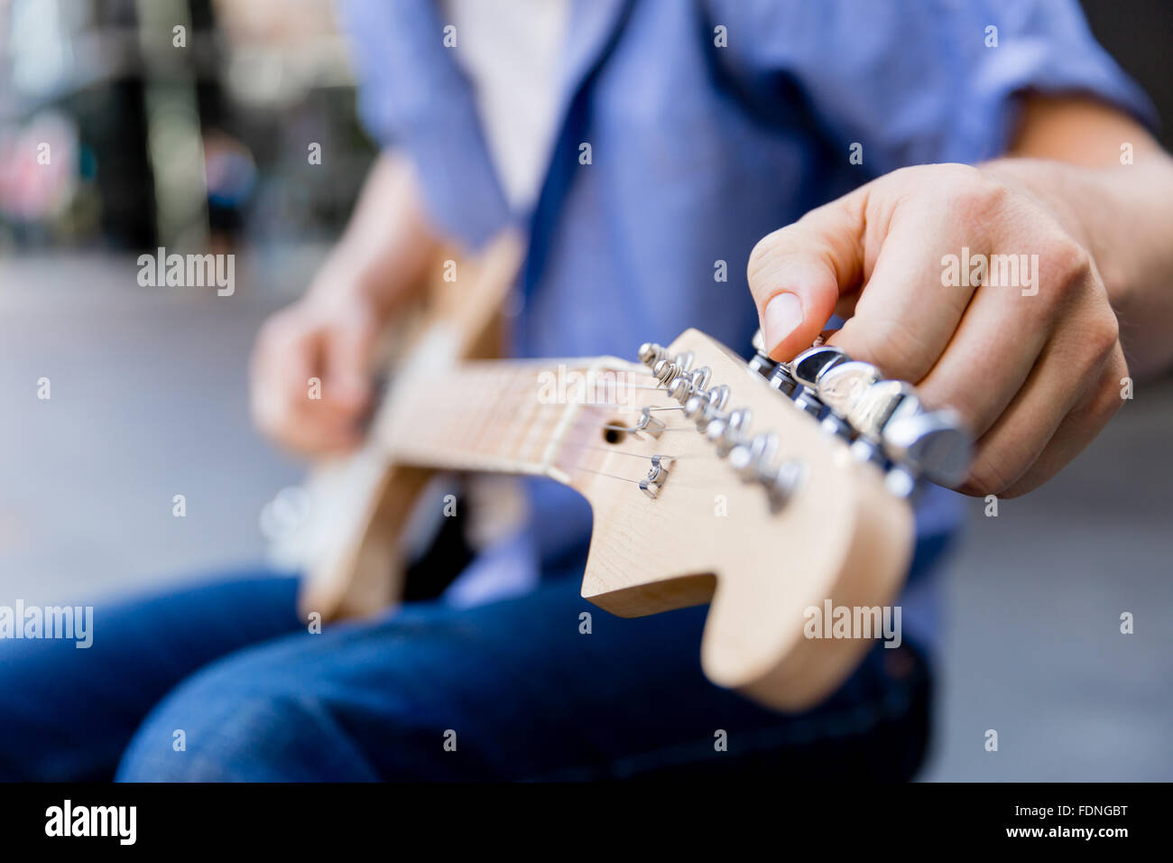 Hands of musician tuning his guitar outside Stock Photo - Alamy