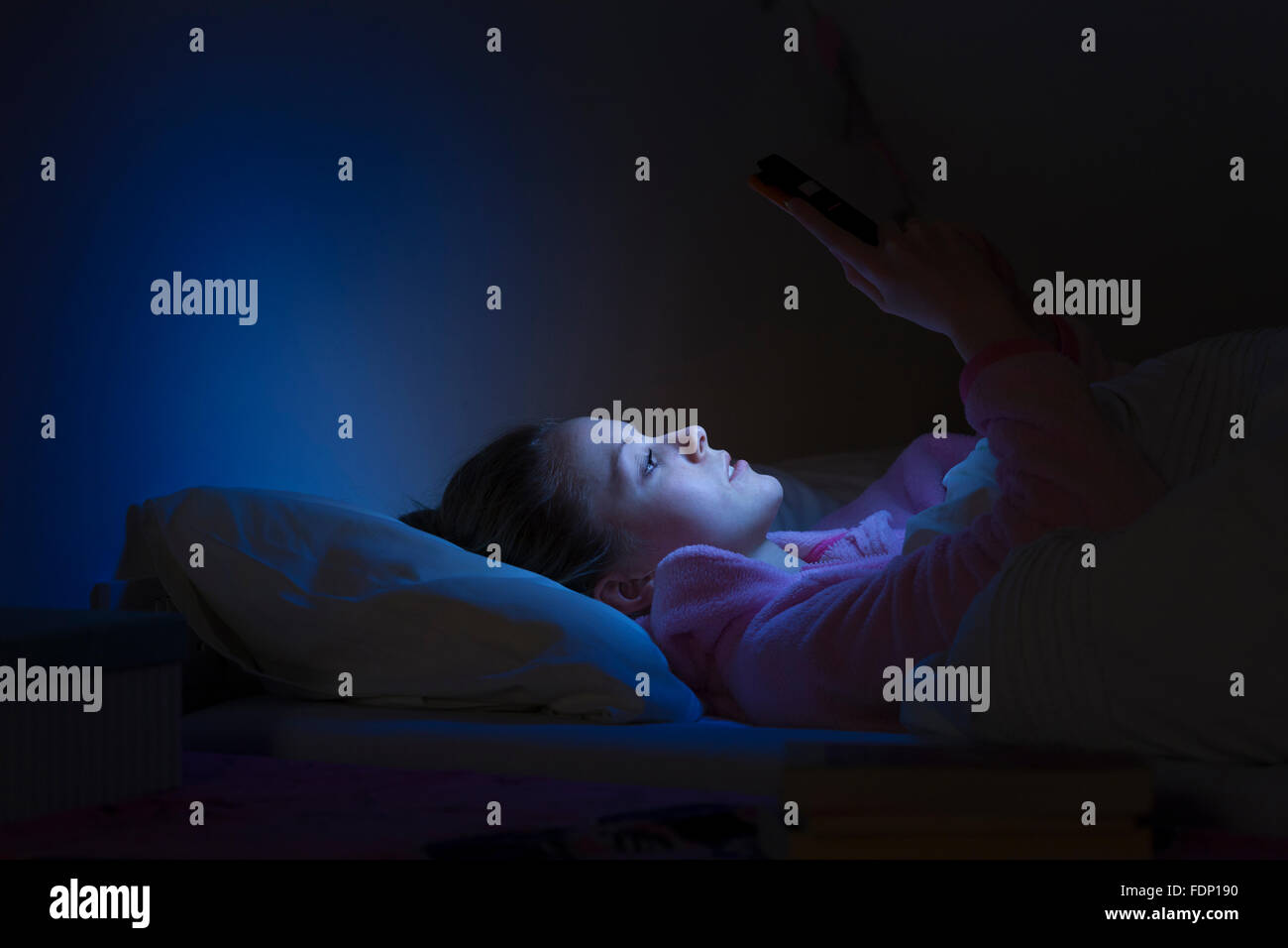 Young teenage girl using smartphone at night in bed. She might be ...